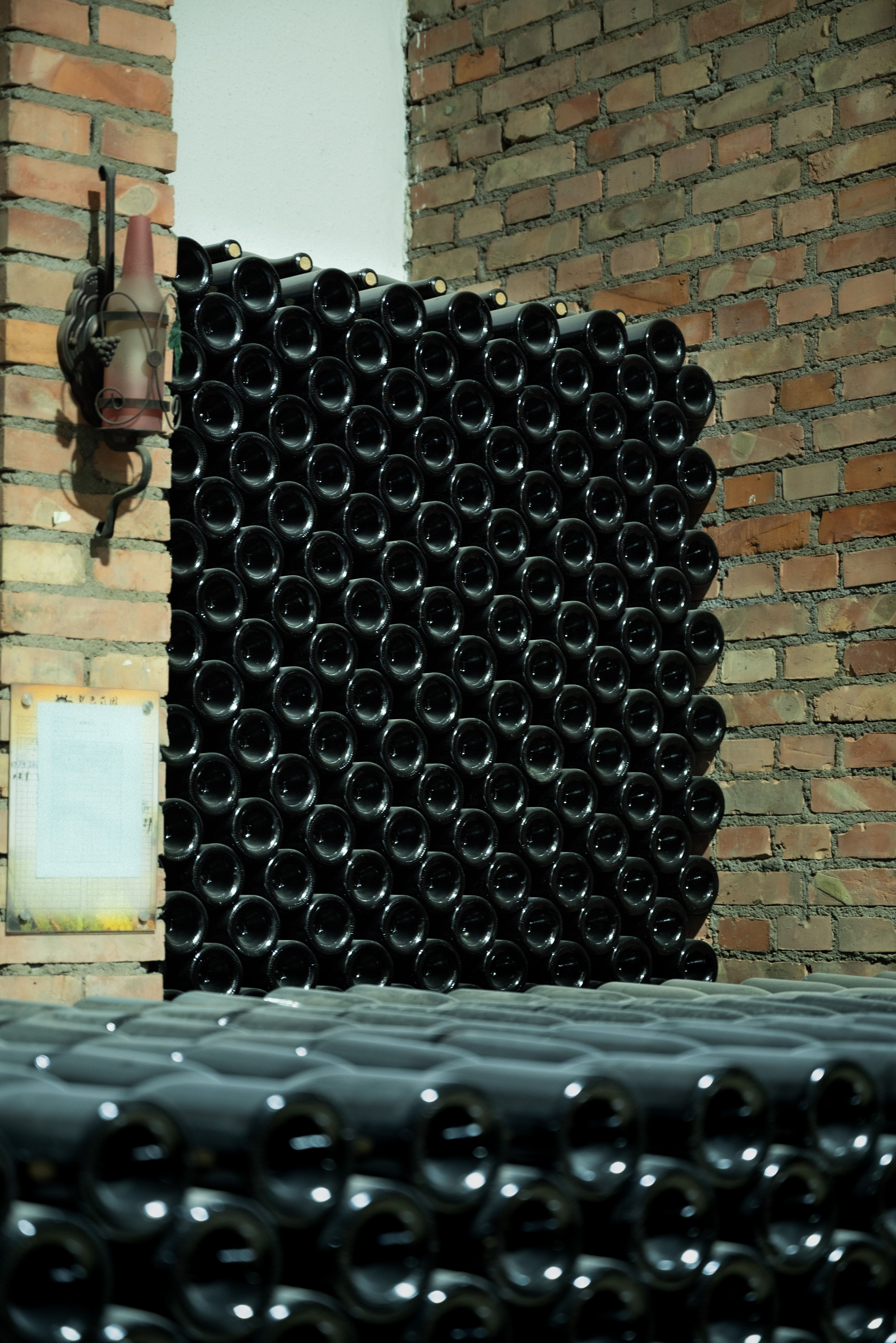 Stacked Wine Bottles in Brick Cellar Wall · Free Stock Photo