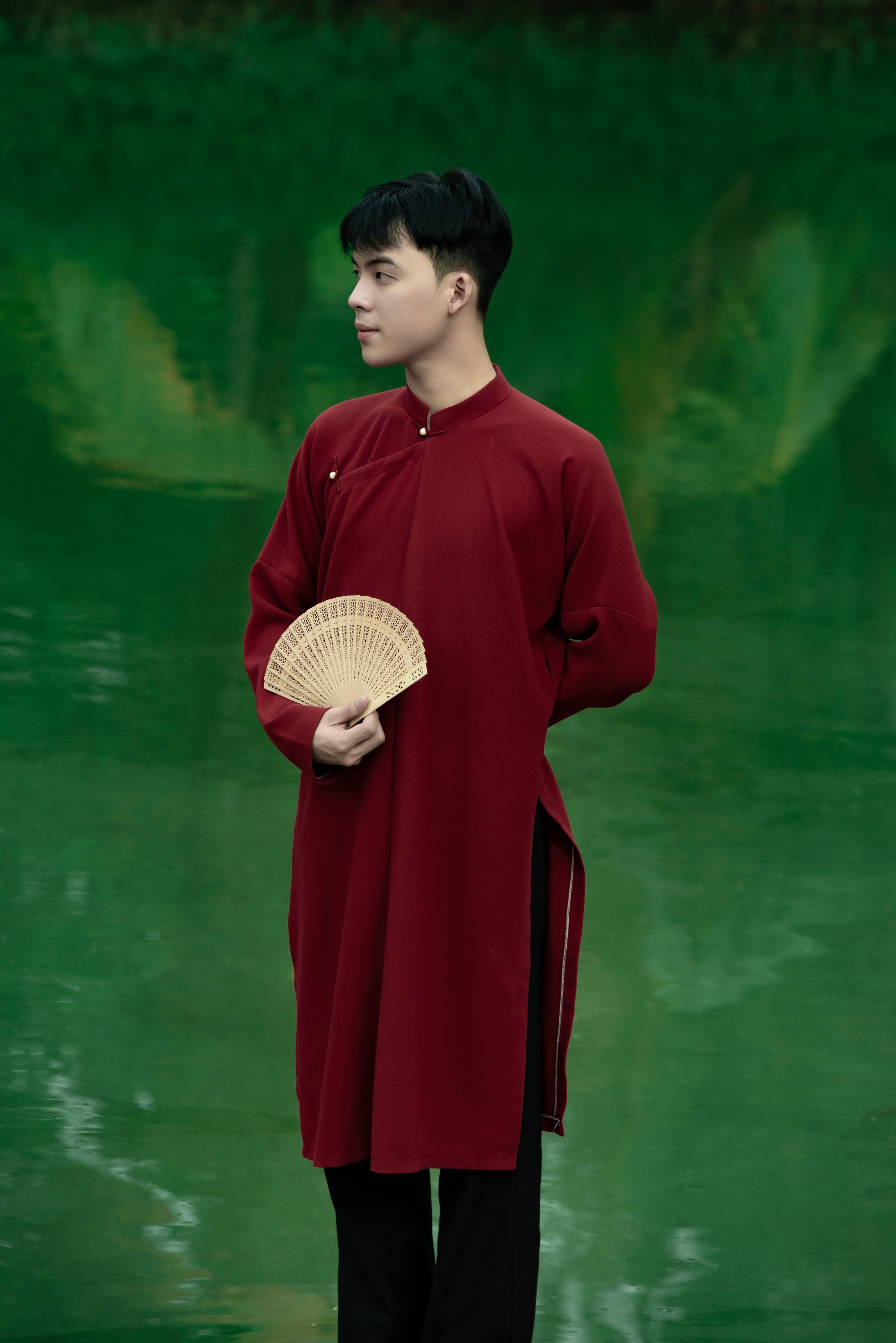 Youth in Traditional Clothing with Fan by Lake · Free Stock Photo
