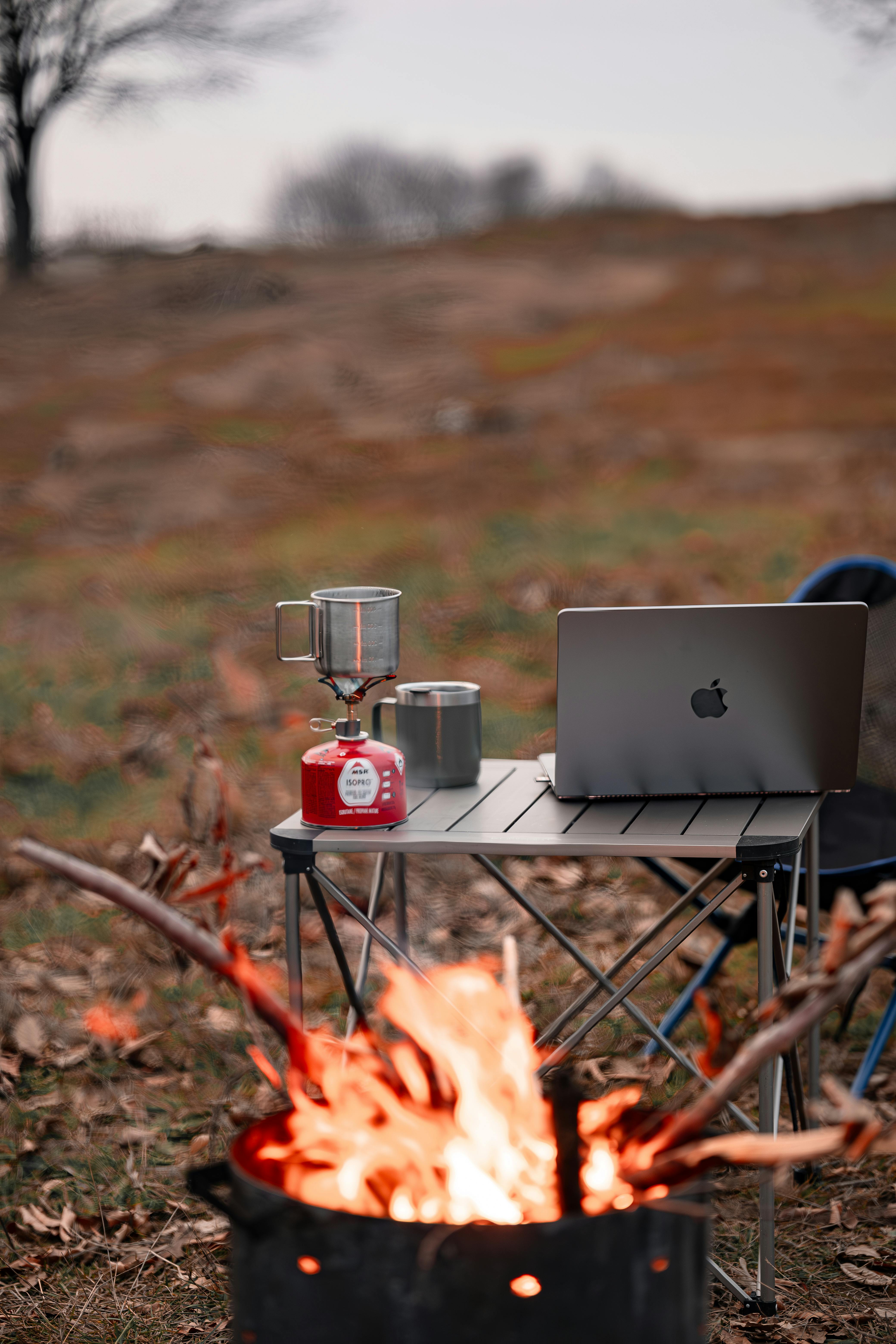 Cozy Outdoor Workspace with Campfire and Laptop · Free Stock Photo