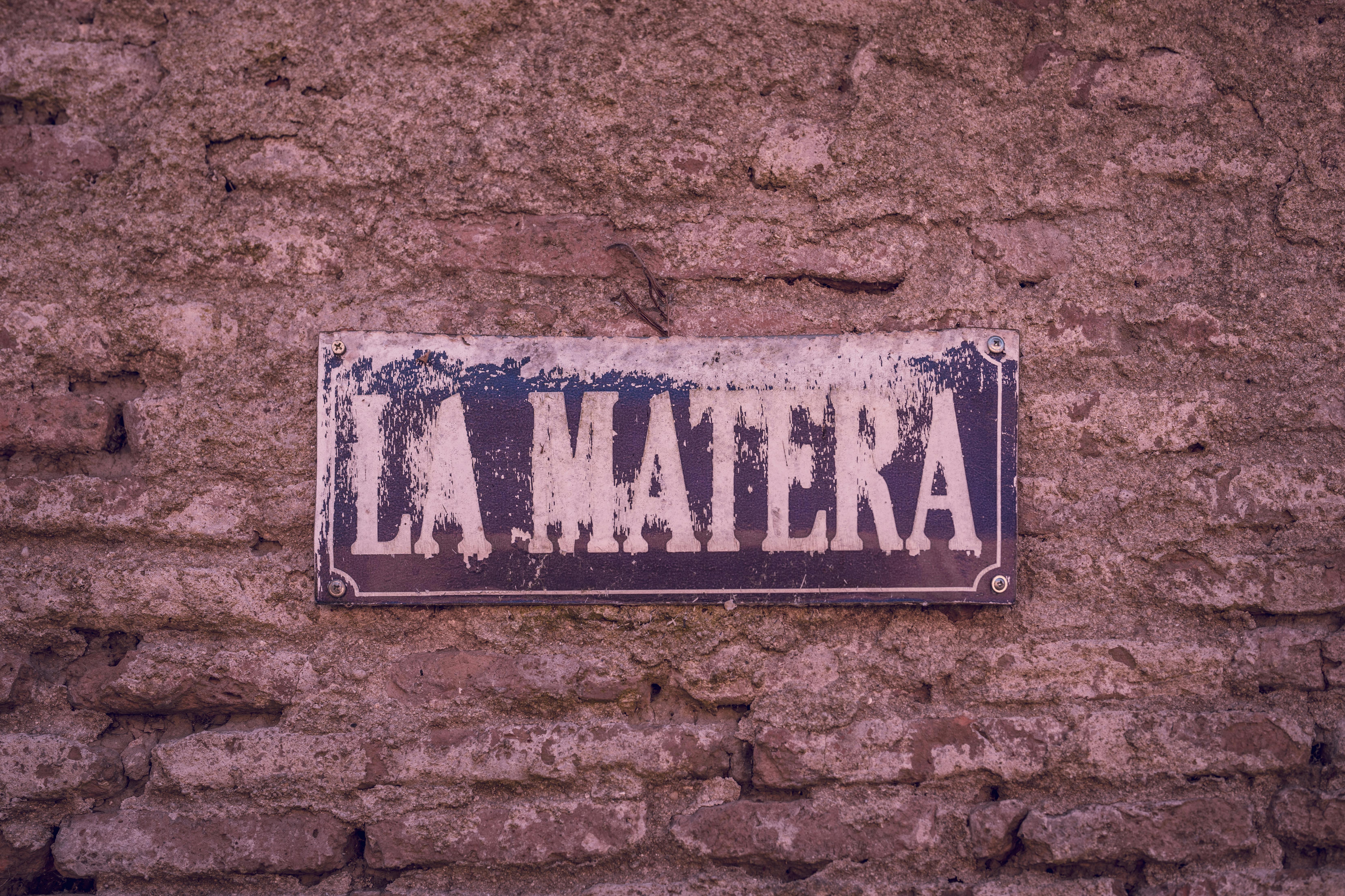 Rustic Sign 'La Matera' on Old Brick Wall · Free Stock Photo