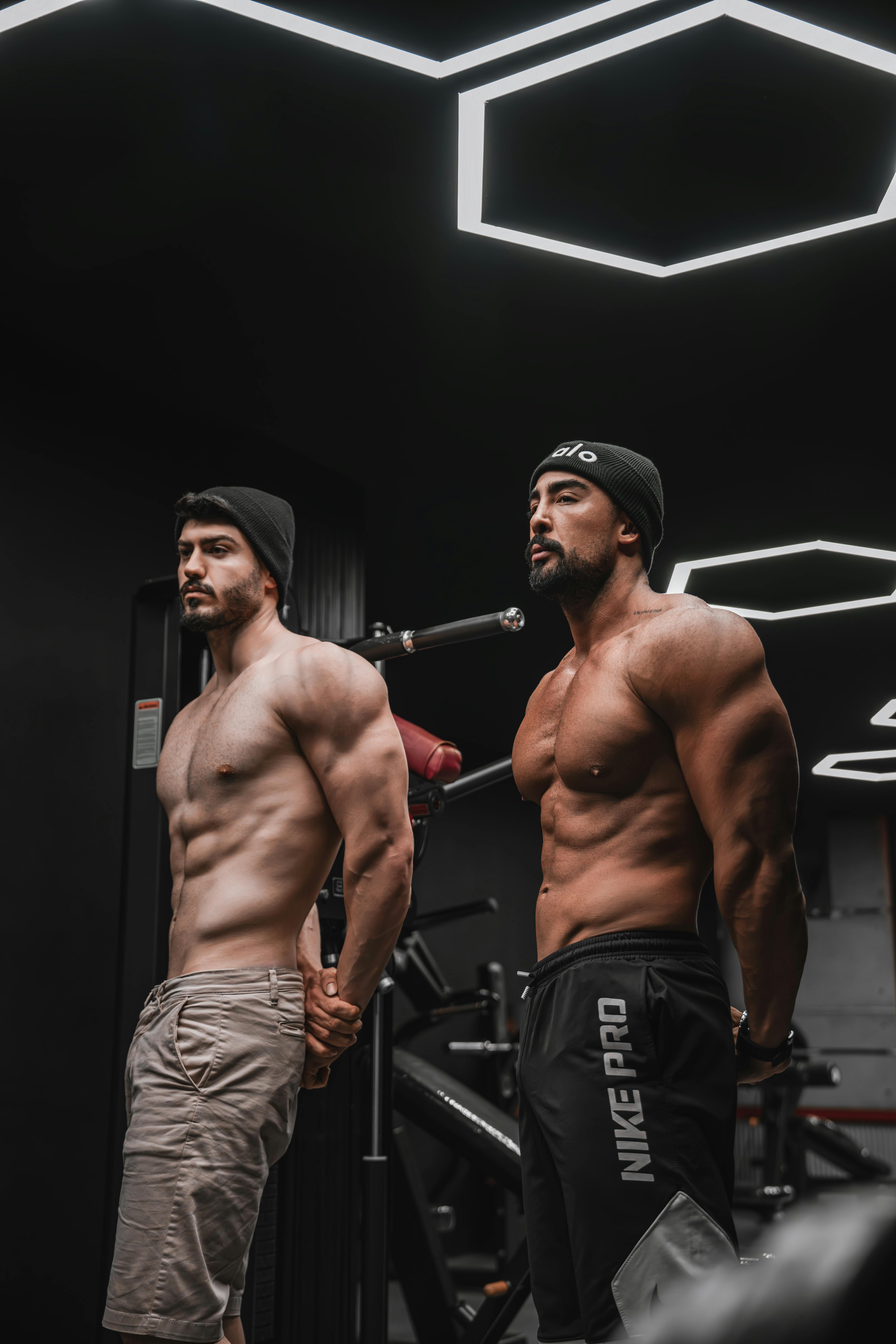 Muscular Men Posing in Gym with Geometric Lighting · Free Stock Photo