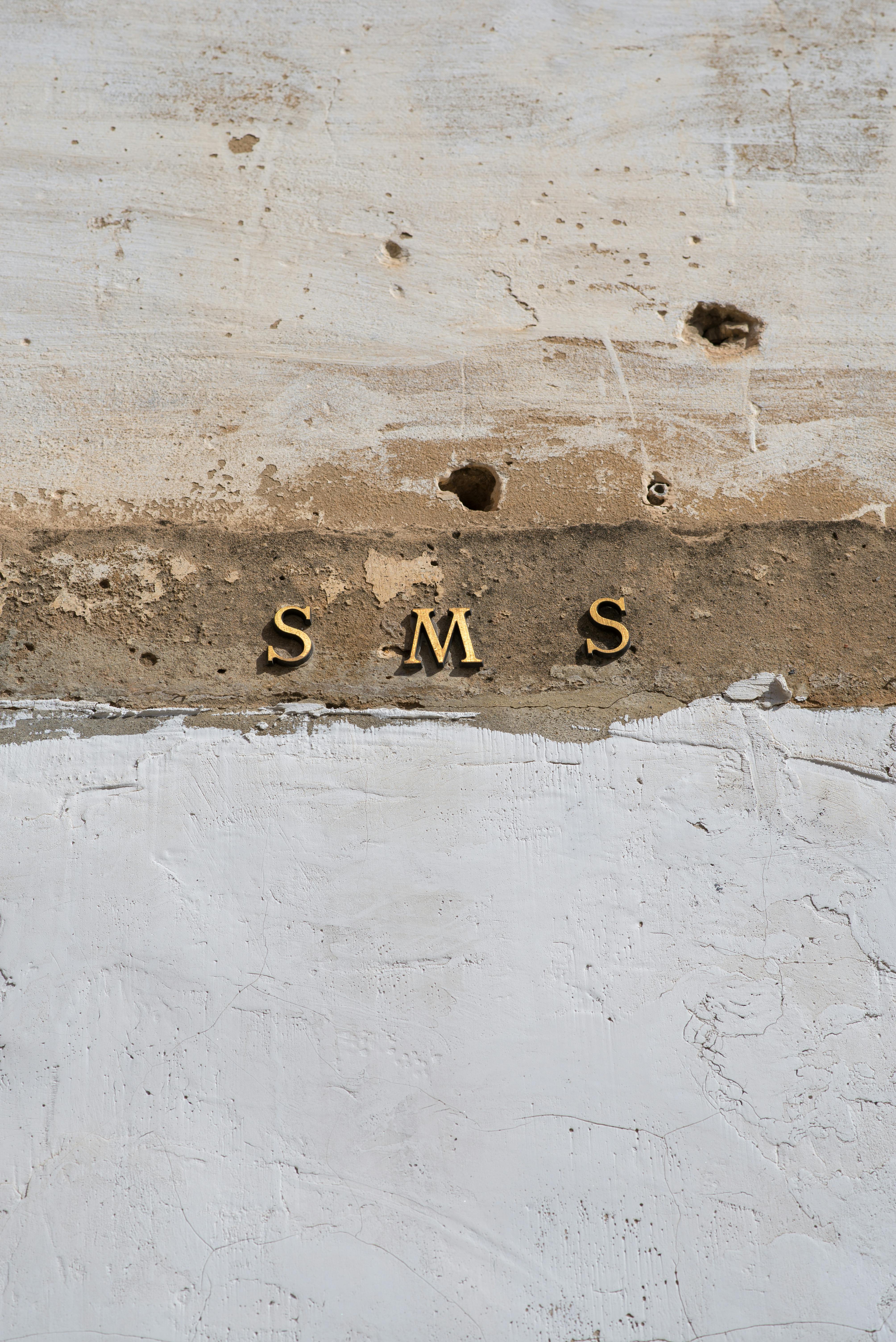 SMS Letters on Weathered Concrete Wall · Free Stock Photo