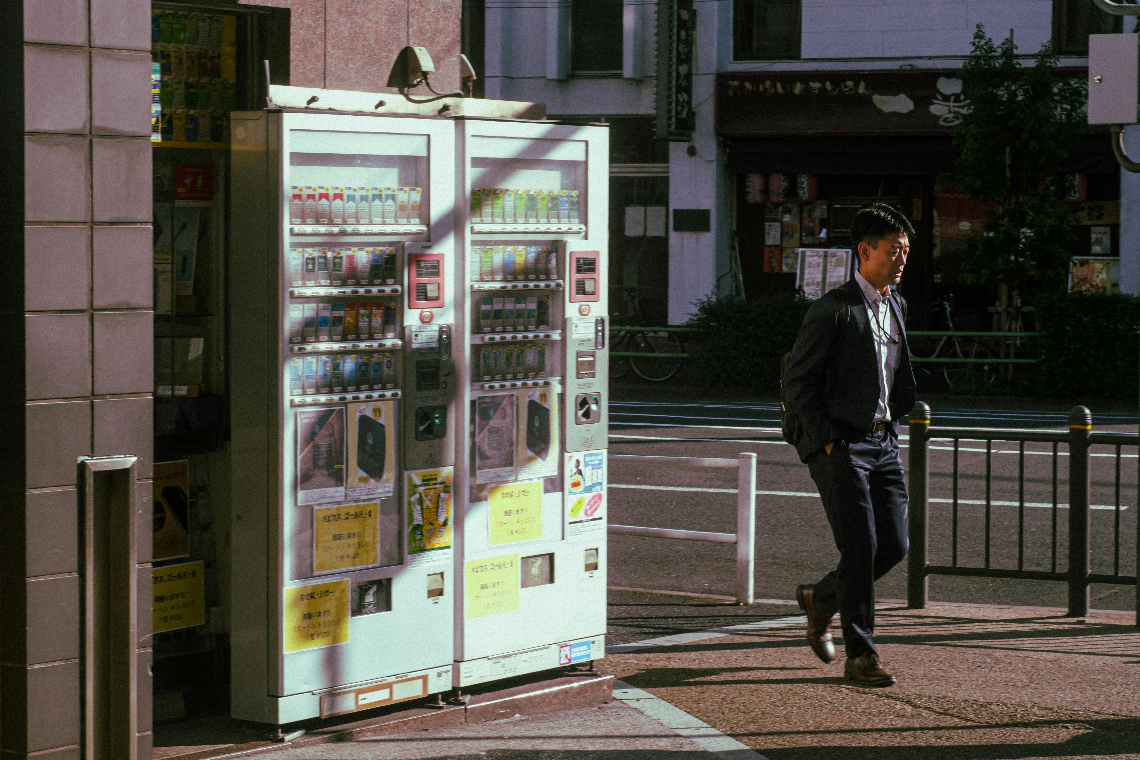 Man Walking Past Vending Machines in Tokyo Street · Free Stock Photo