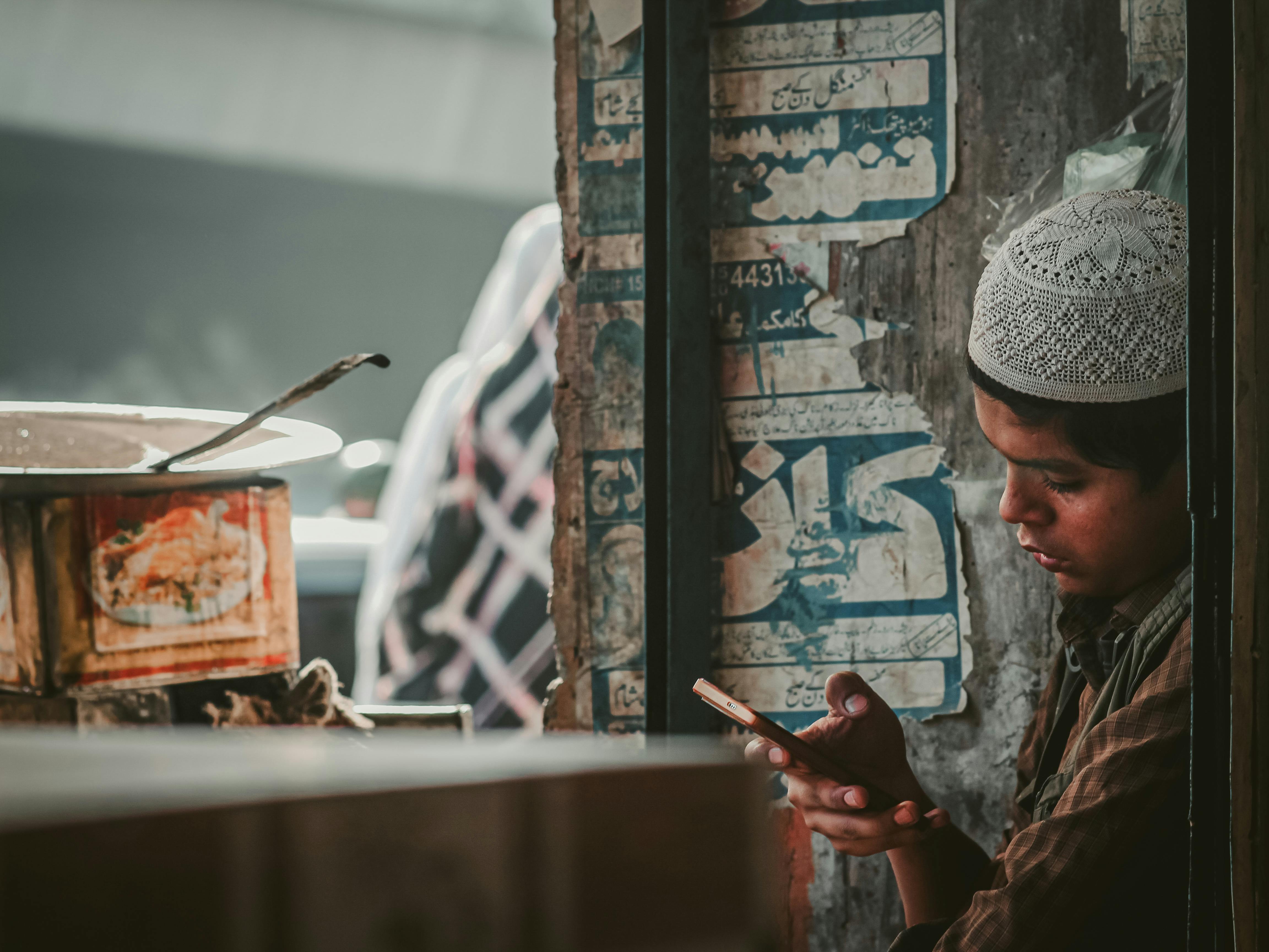Young Boy Using Smartphone in Urban Pakistan · Free Stock Photo
