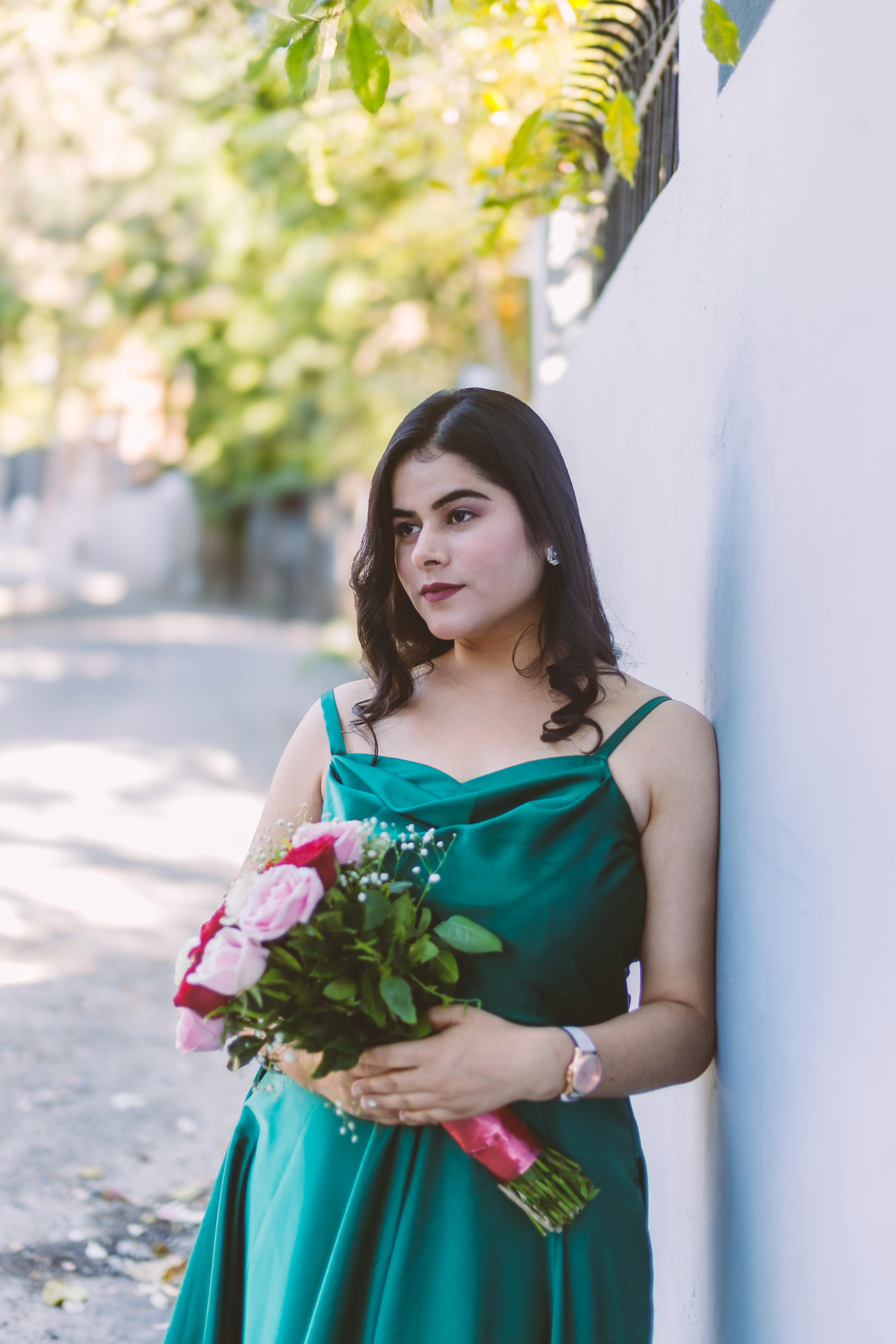 Elegant Woman in Green Dress Holding Roses Outdoors · Free Stock Photo