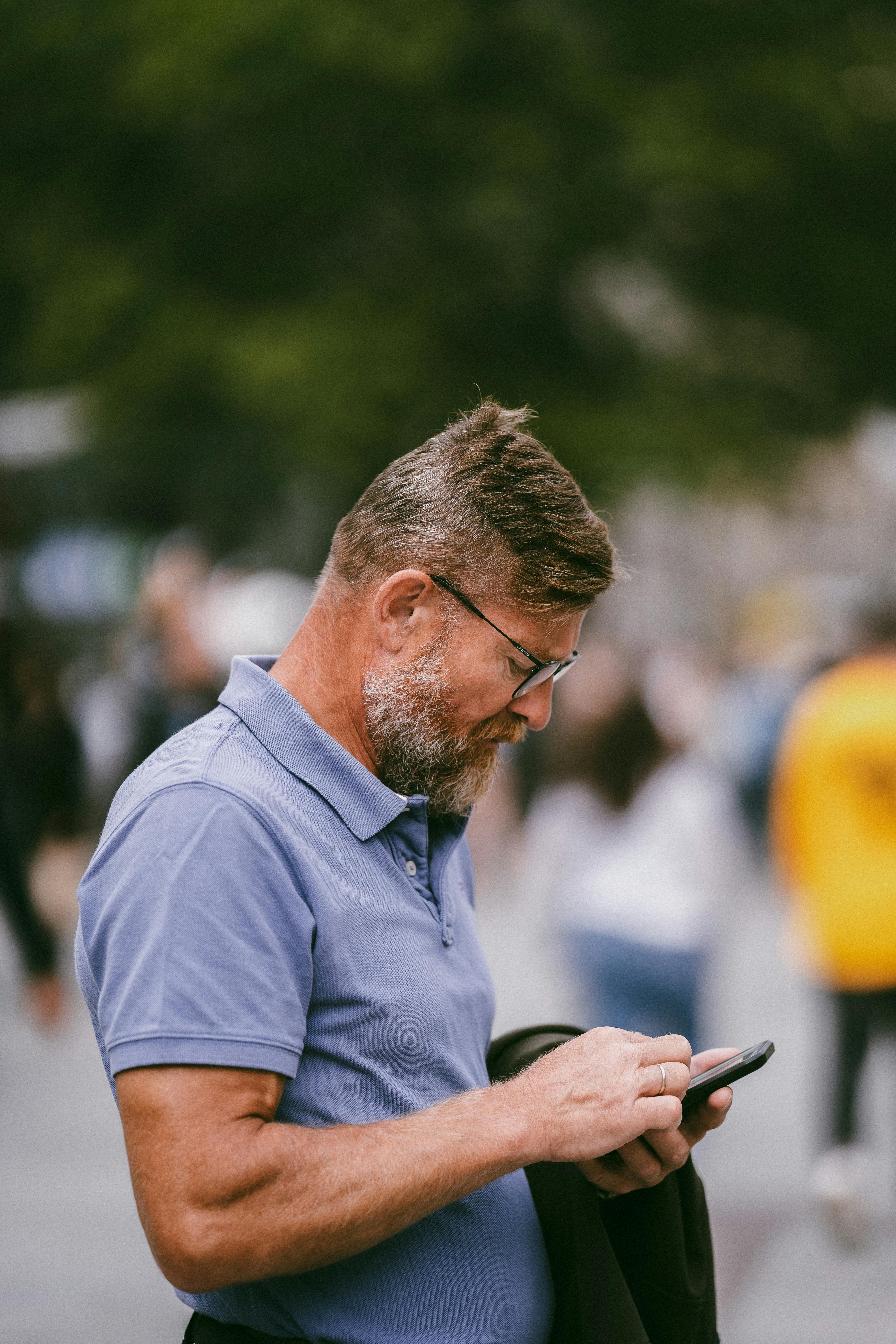Man Checking Phone in Urban Street Scene · Free Stock Photo