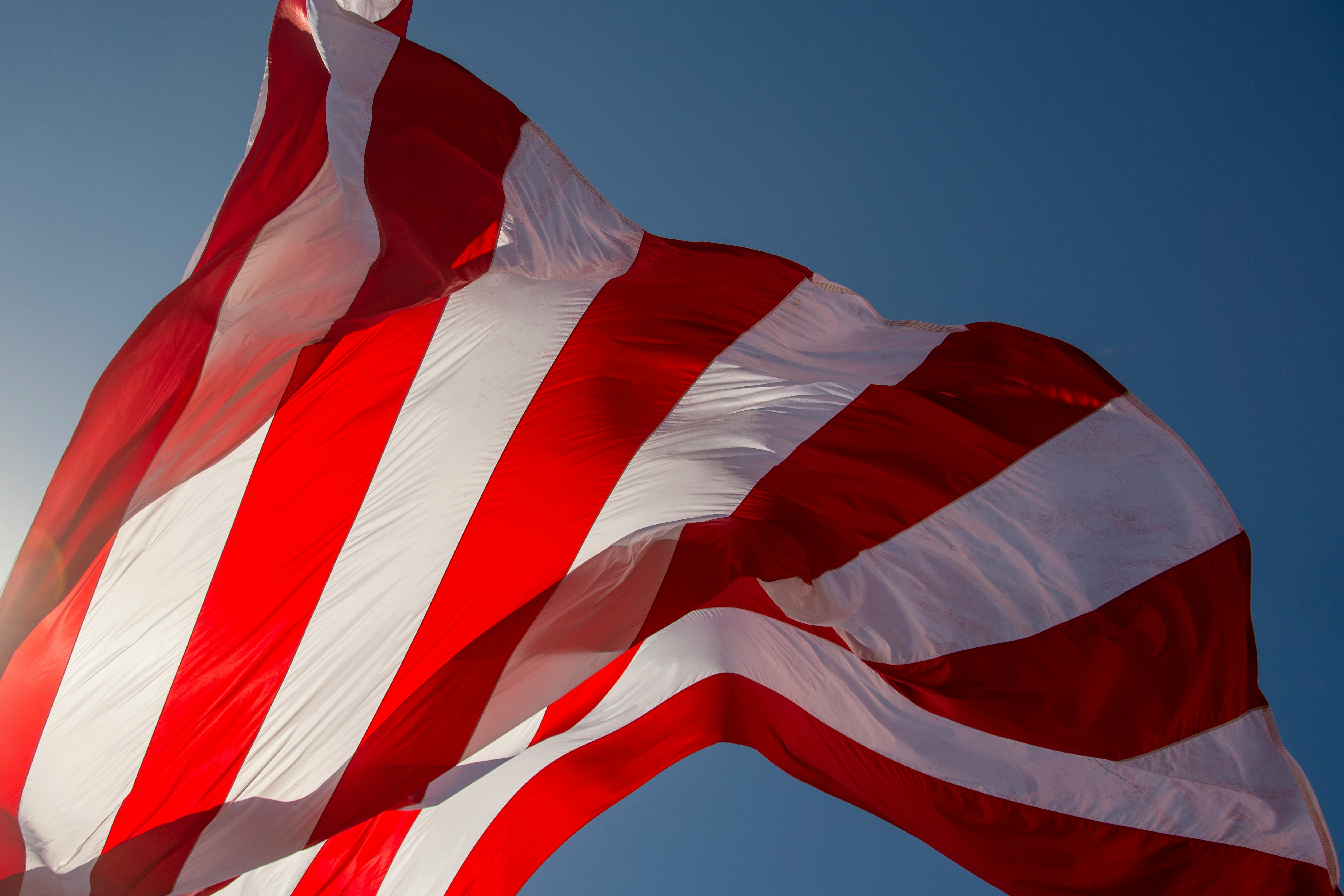 Red and White Striped Flag Waving in Blue Sky · Free Stock Photo