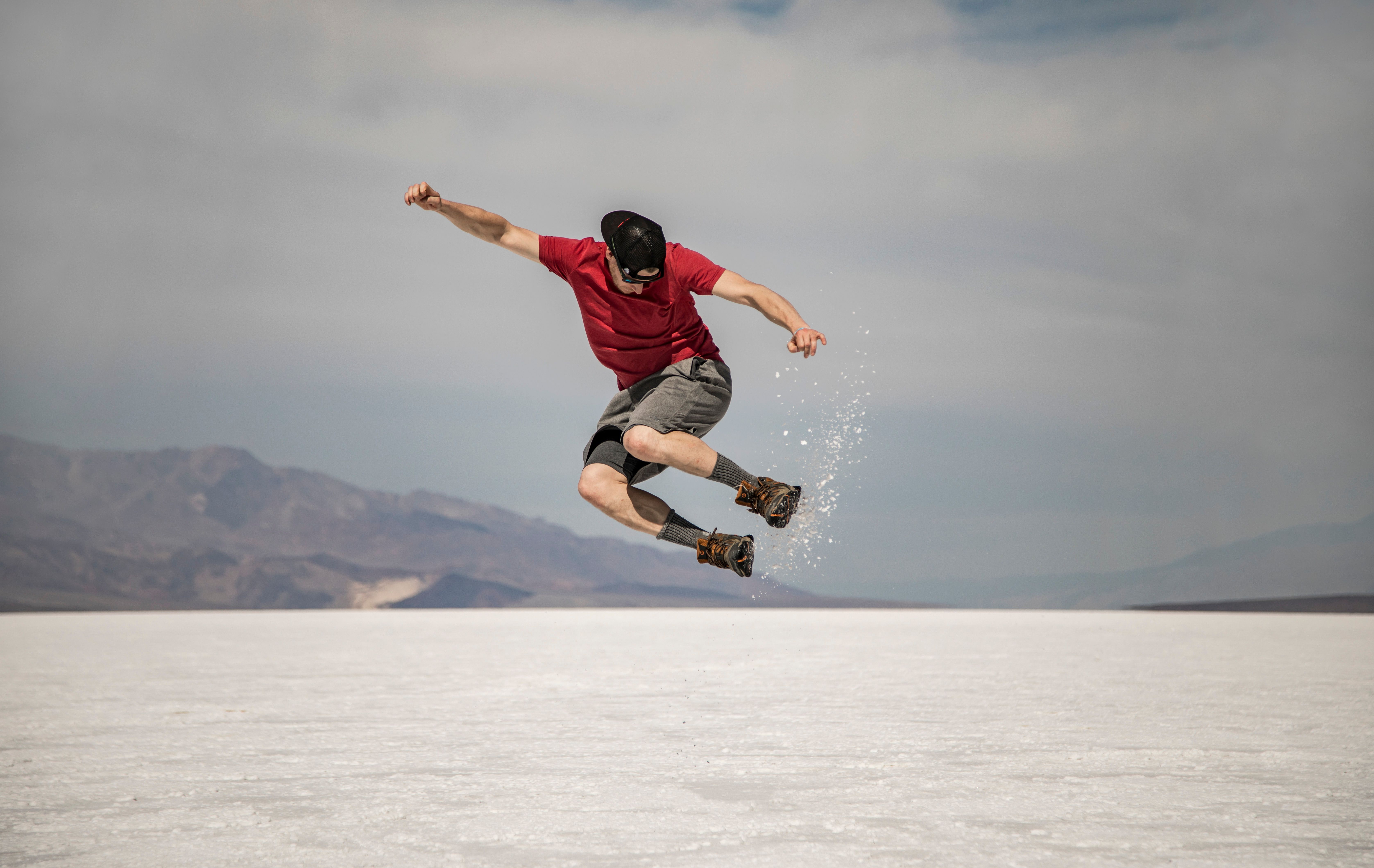 Man Jumping on Salt Flats in Red Shirt · Free Stock Photo