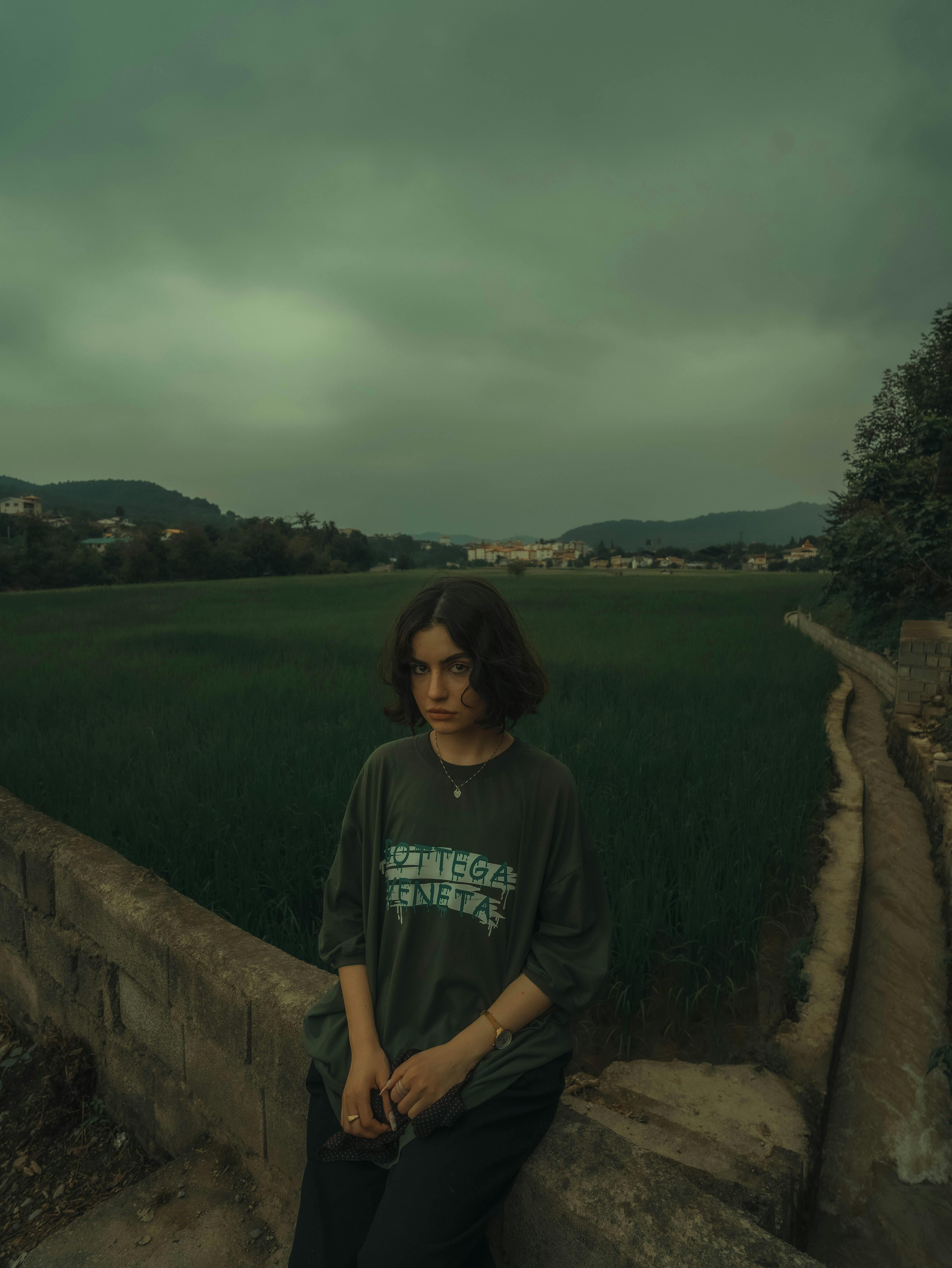 Pensive Woman in Dark Green Field Landscape · Free Stock Photo