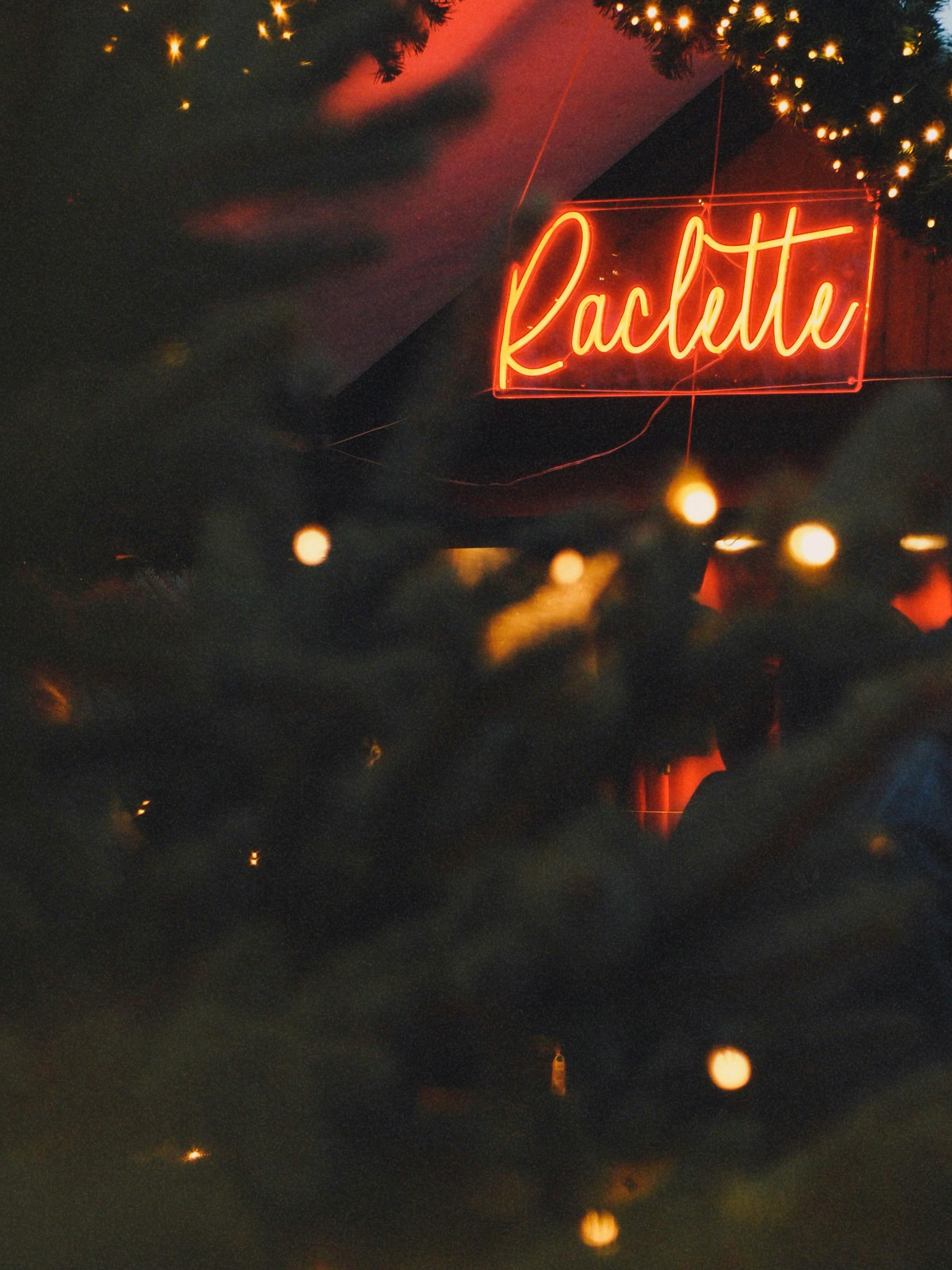 Christmas Market Scene with Raclette Sign · Free Stock Photo