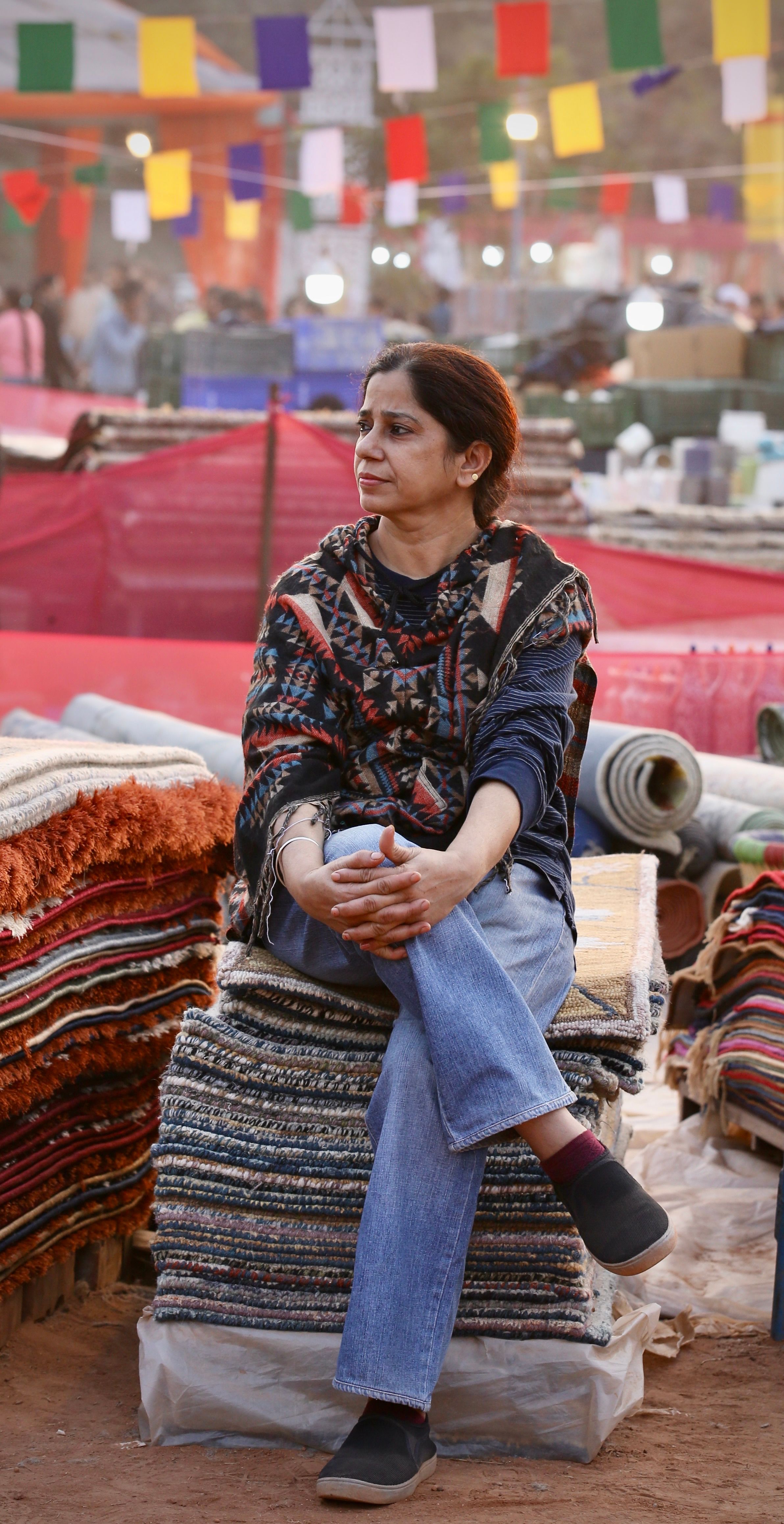 Woman Sitting on Rugs at Vibrant Outdoor Market · Free Stock Photo