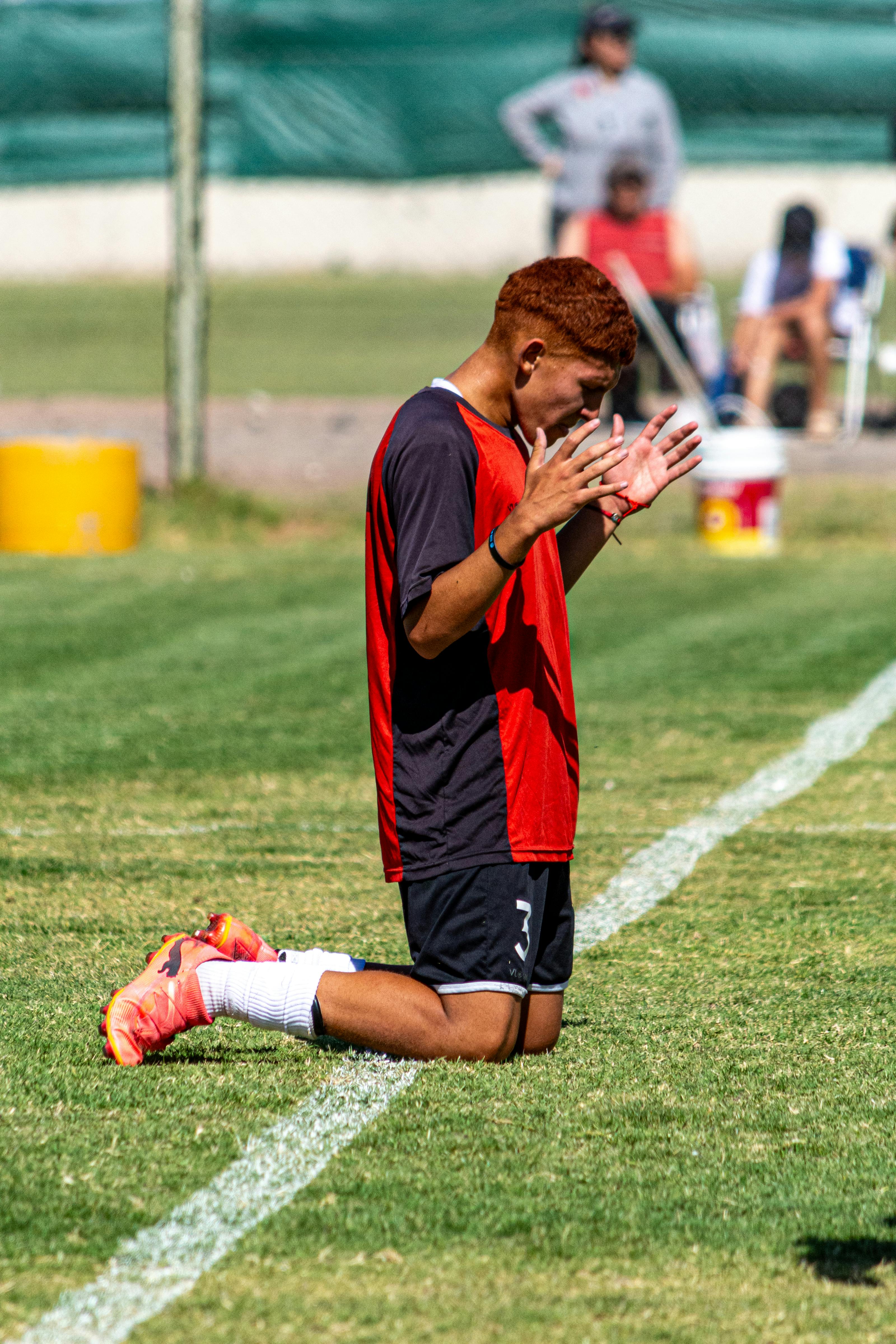 Young Soccer Player Kneeling on Field · Free Stock Photo