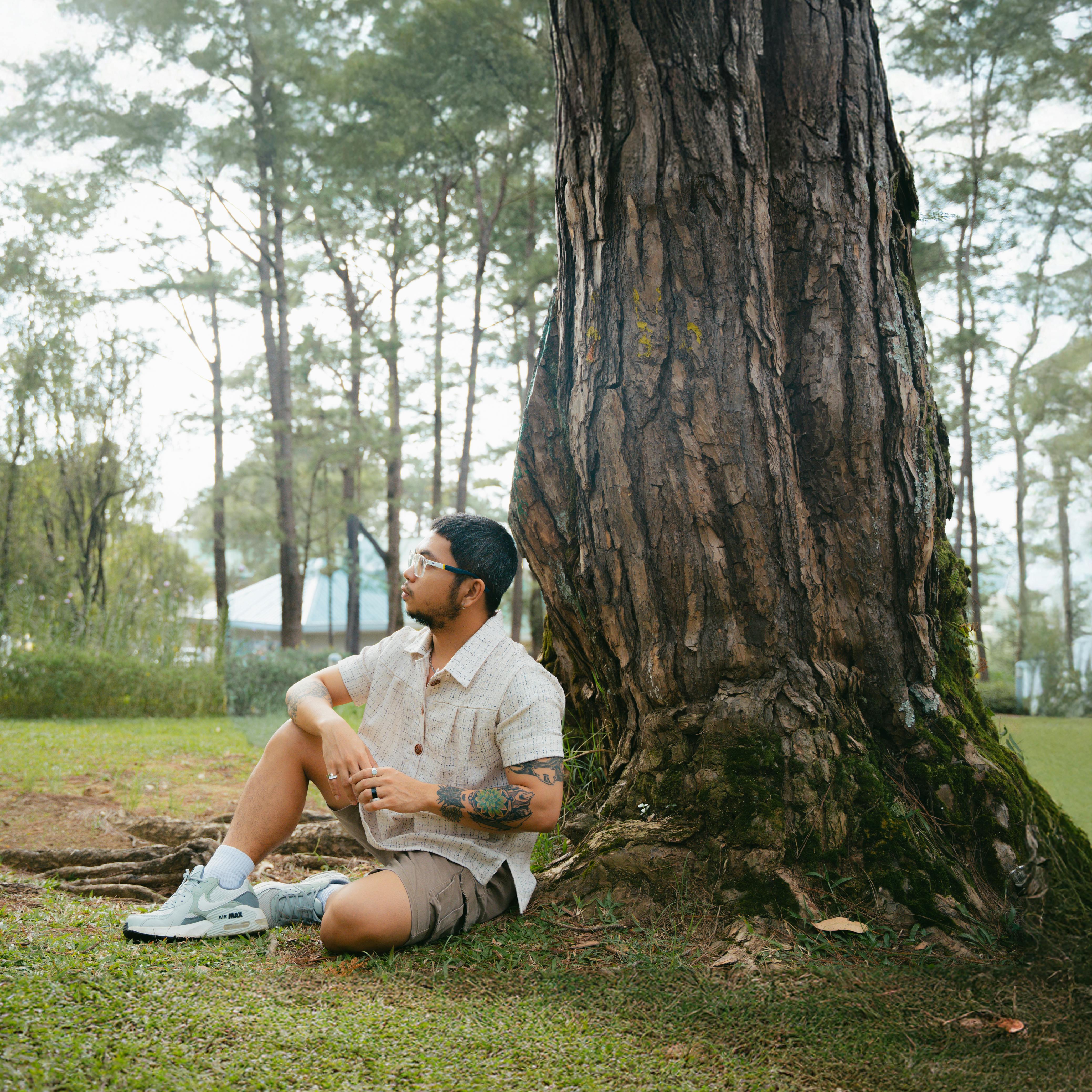 Man Relaxing Under Large Tree in Park Setting · Free Stock Photo