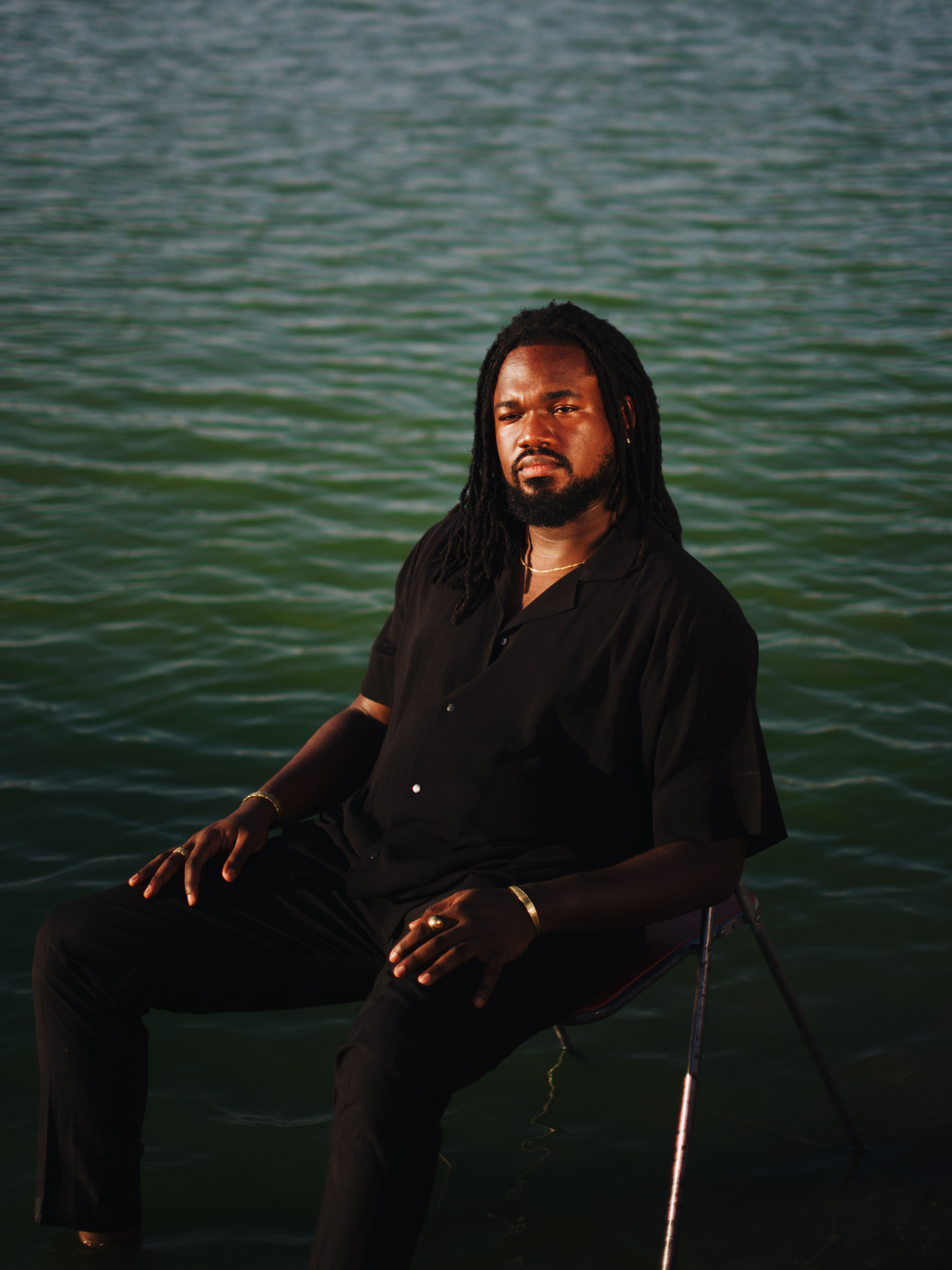 Portrait of a Man Sitting by Water at Dusk · Free Stock Photo