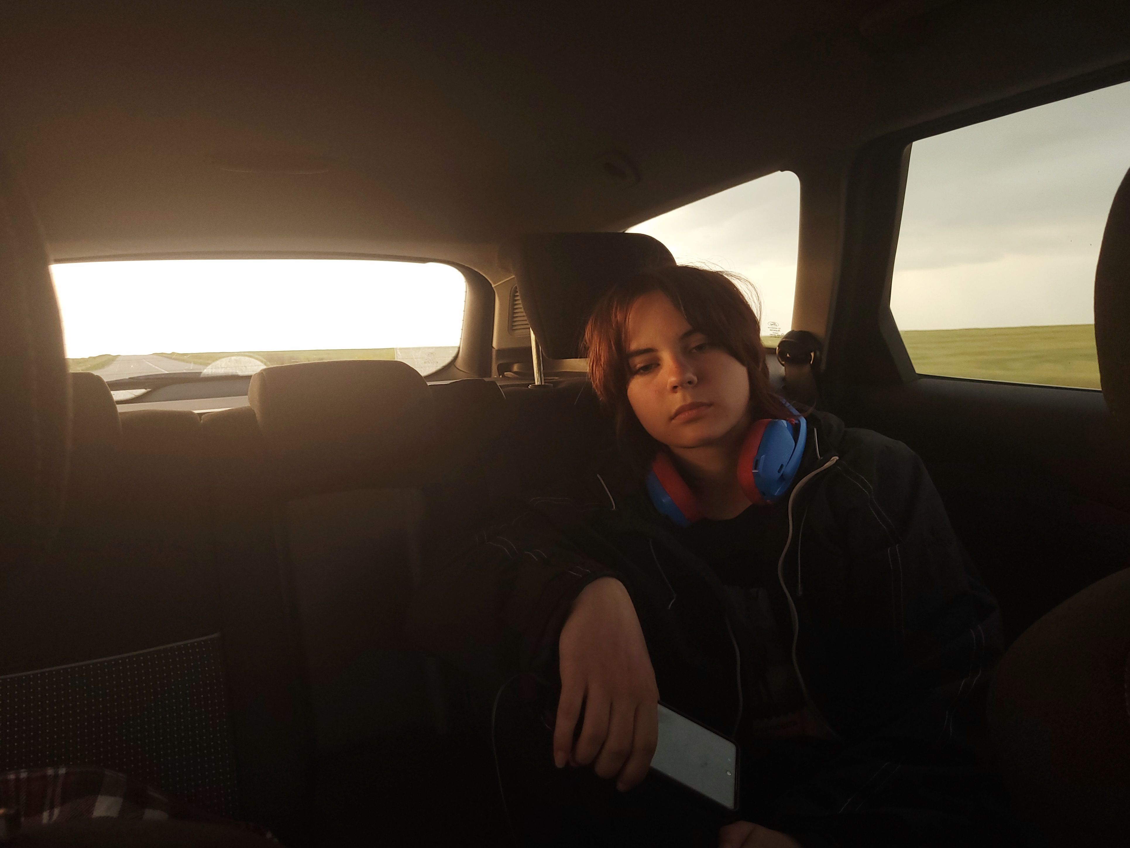 Teen Relaxing in Car with Headphones at Sunset · Free Stock Photo
