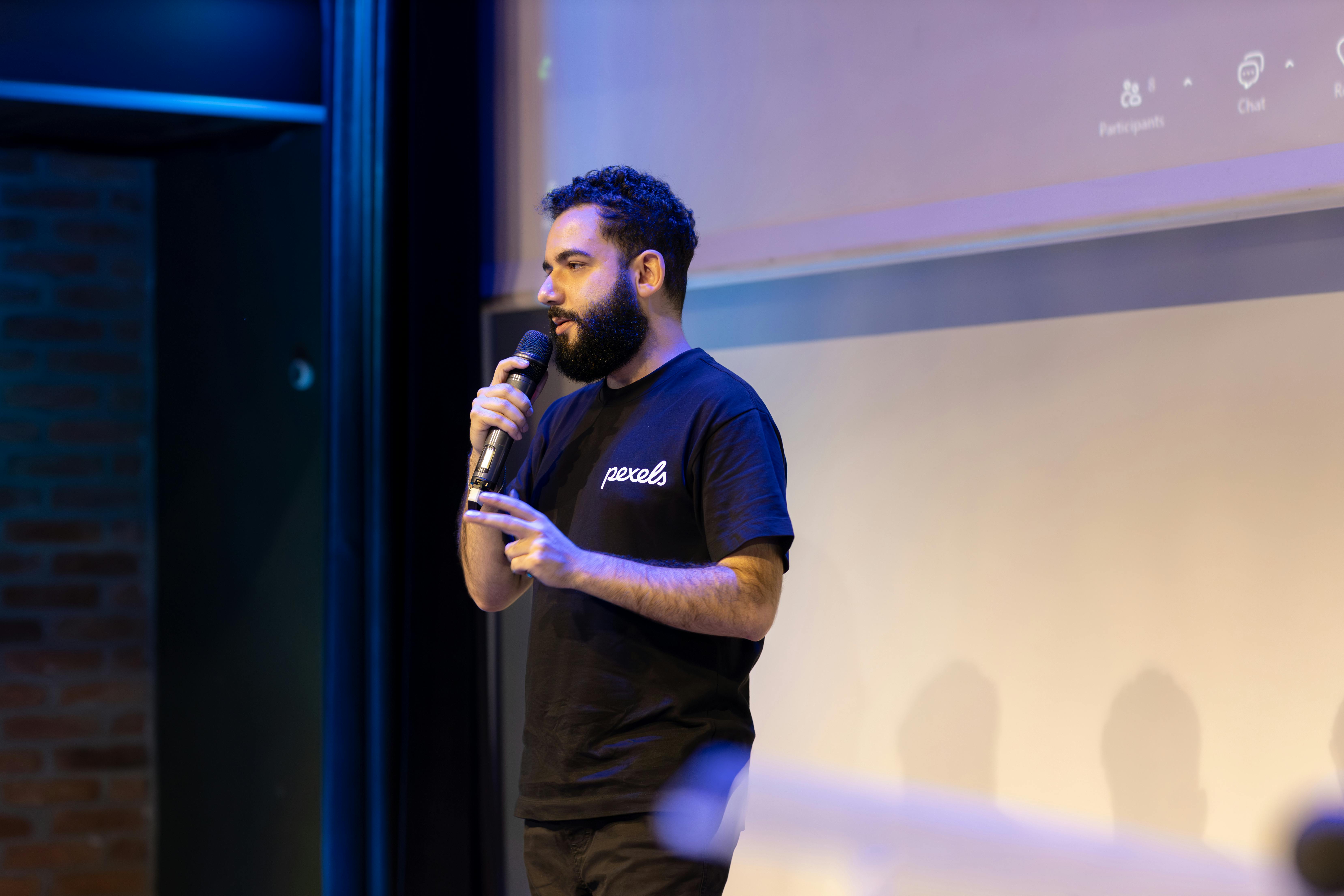 Man Giving Presentation on Stage with Microphone · Free Stock Photo