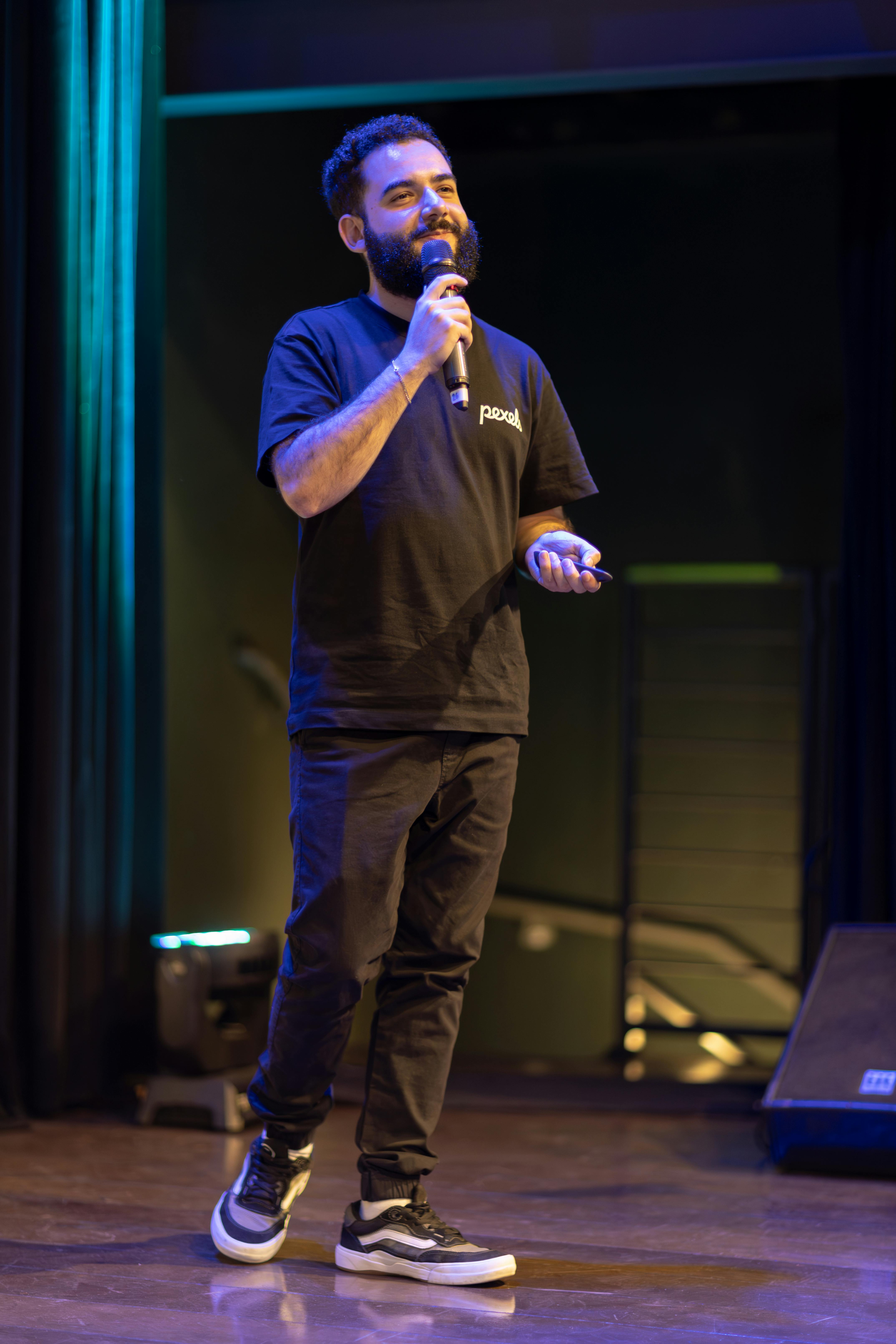 Man Speaking in Front of an Audience with Microphone · Free Stock Photo