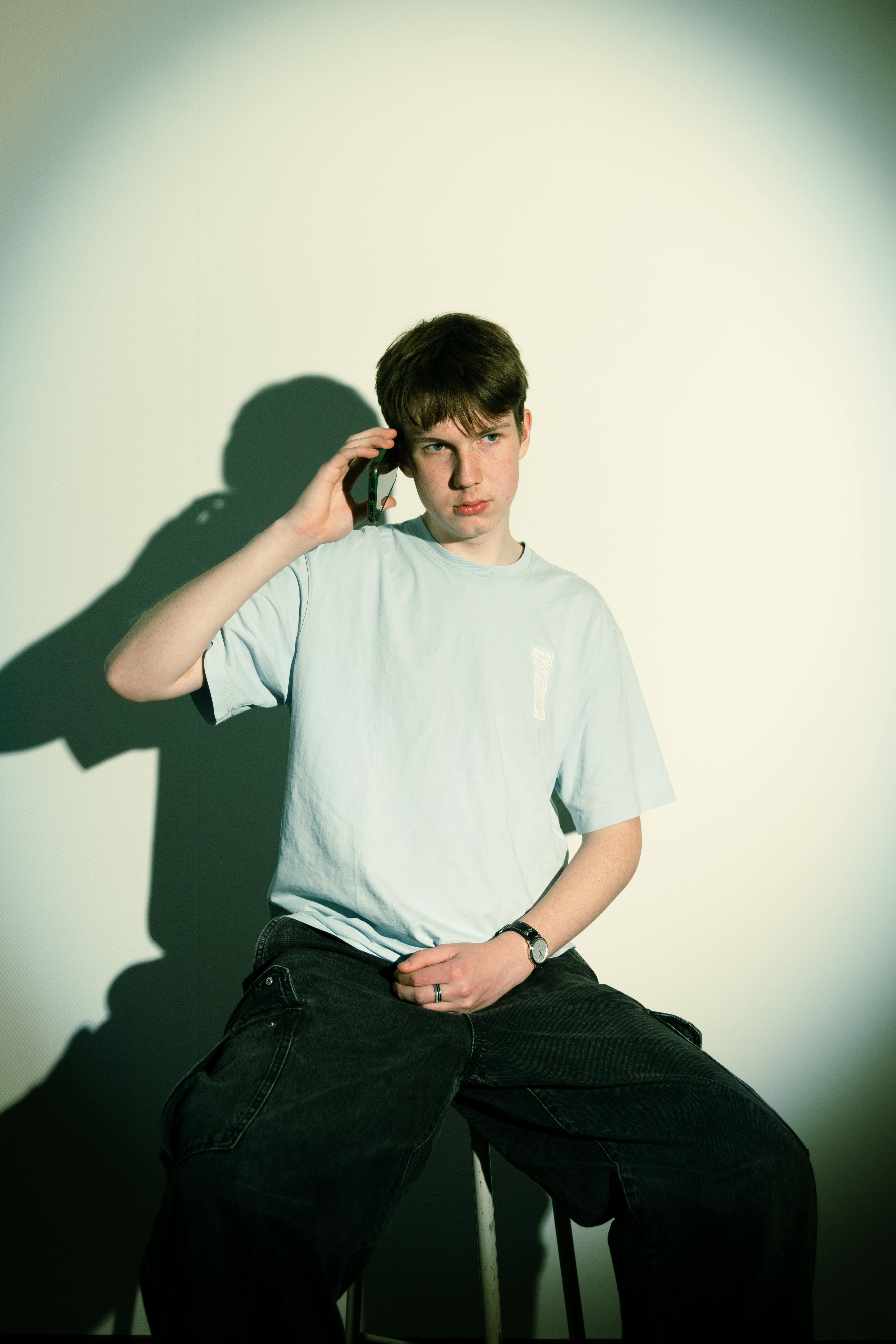 Young Male Sitting in Dramatic Shadow Lighting · Free Stock Photo