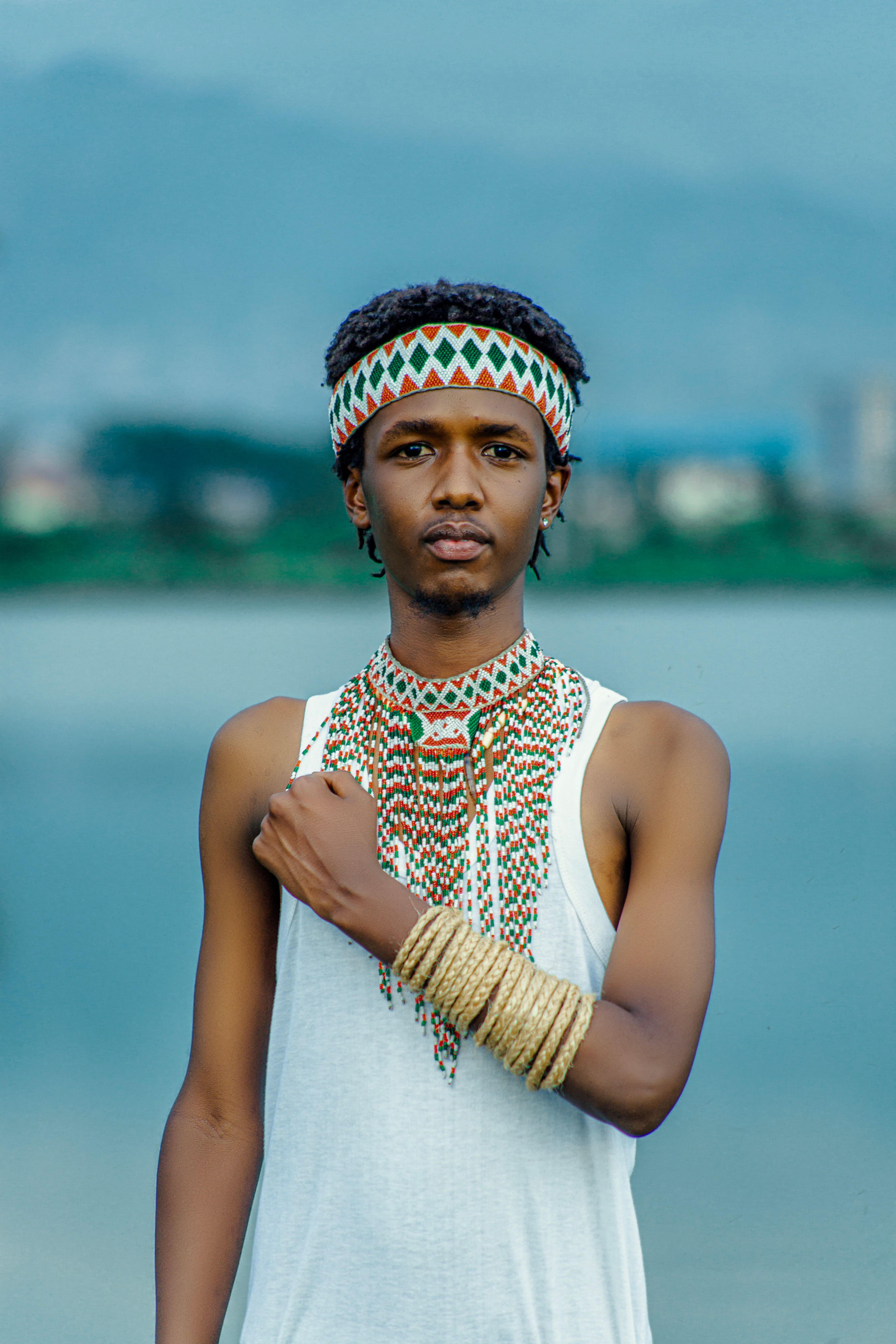 Young Man in Traditional Beaded Attire by Lake · Free Stock Photo