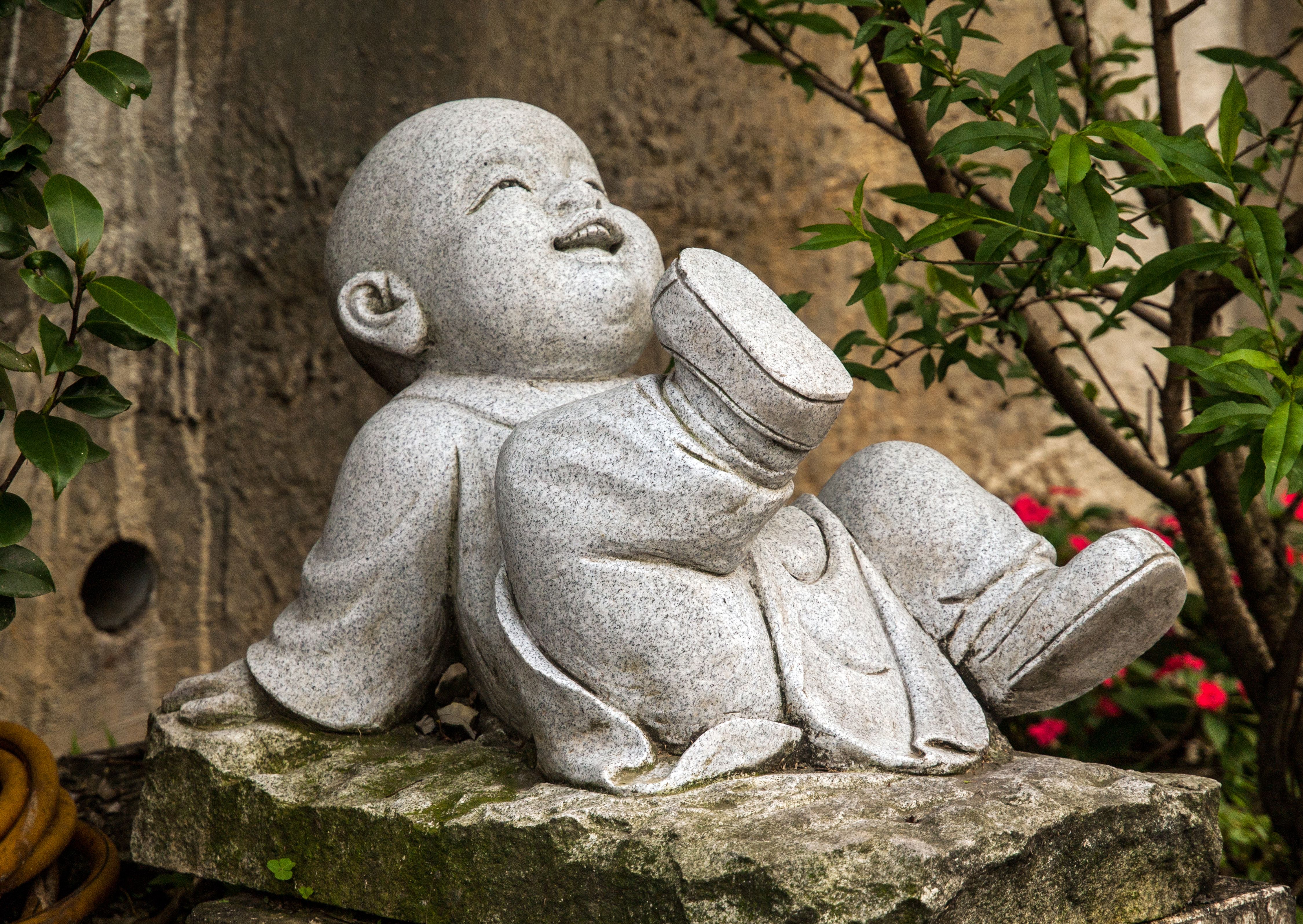 Charming Stone Baby Monk Statue in Garden Setting · Free Stock Photo