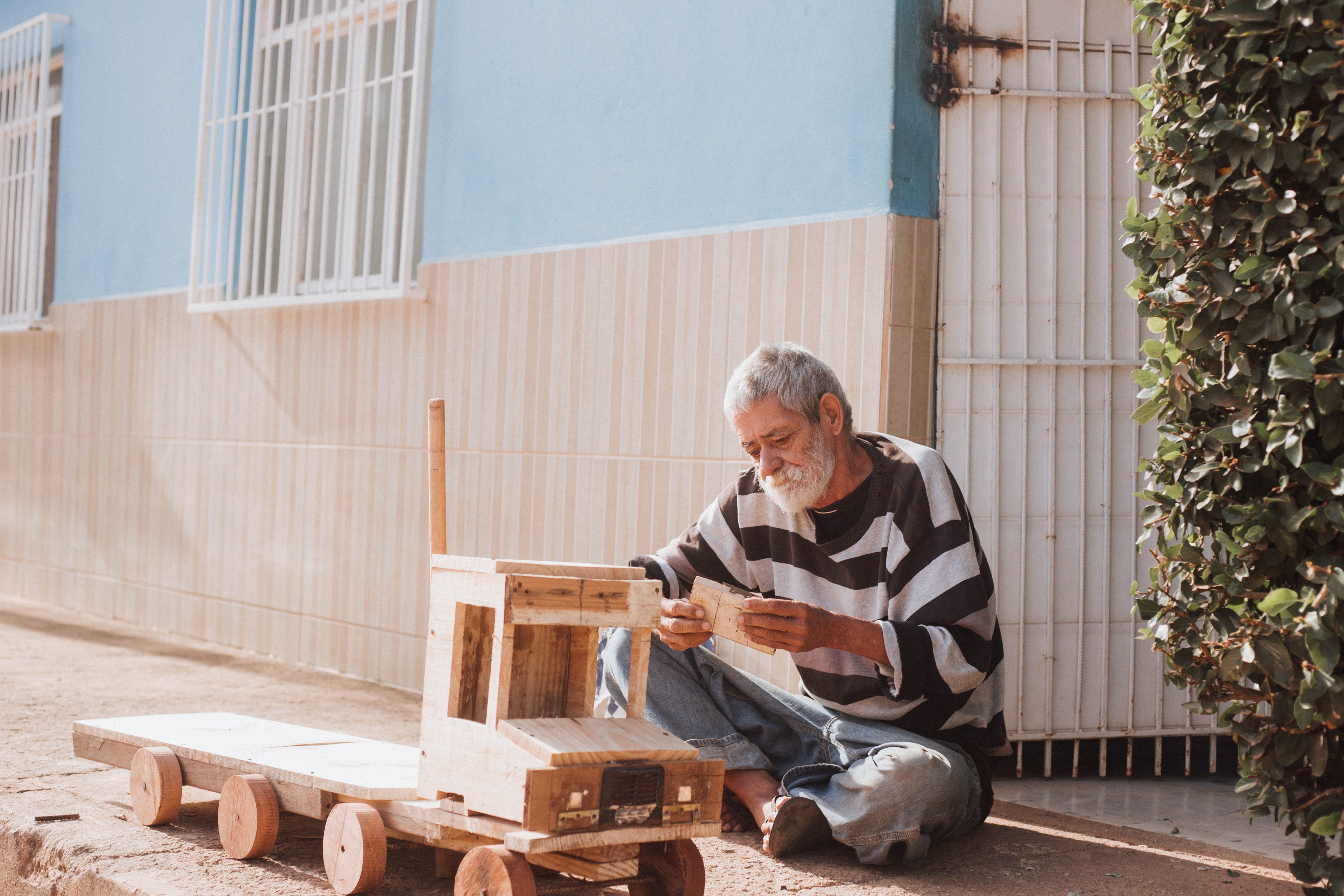 Elderly Man Crafting Wooden Toy Outdoors · Free Stock Photo