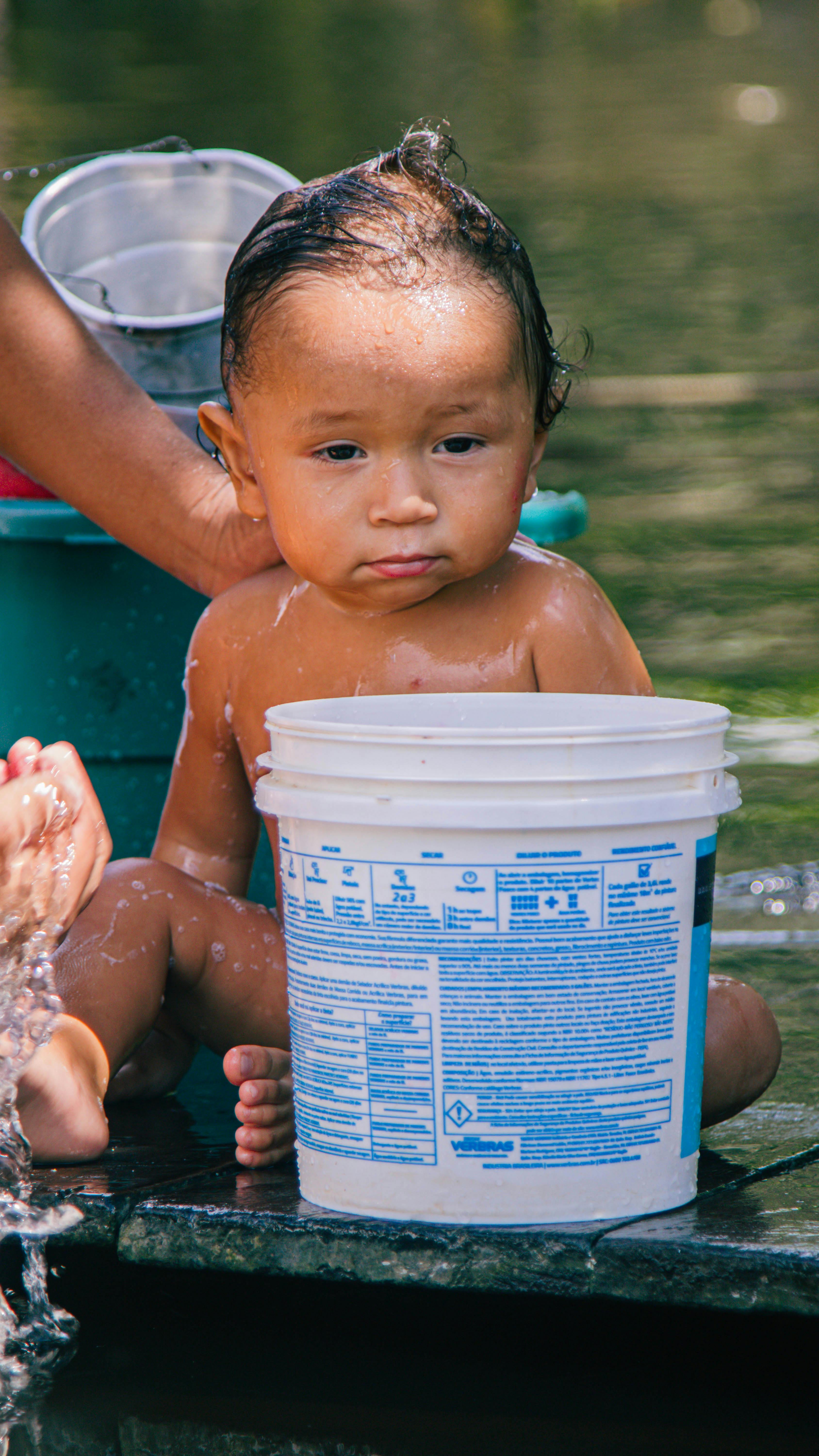 Cute Baby Bathing Outdoors with Water Bucket · Free Stock Photo