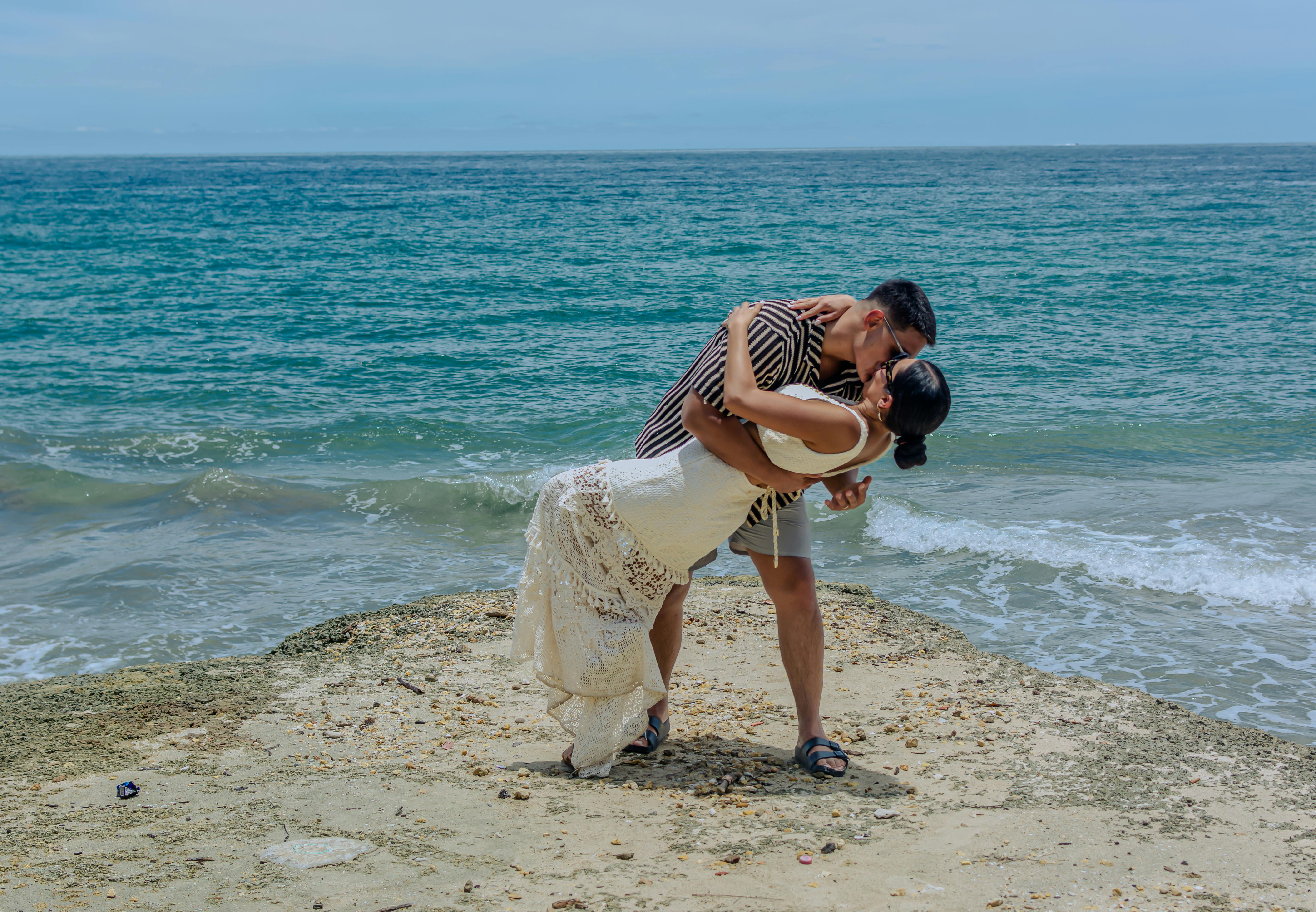 Couple Romantic Kiss on Scenic Beach Shoreline · Free Stock Photo