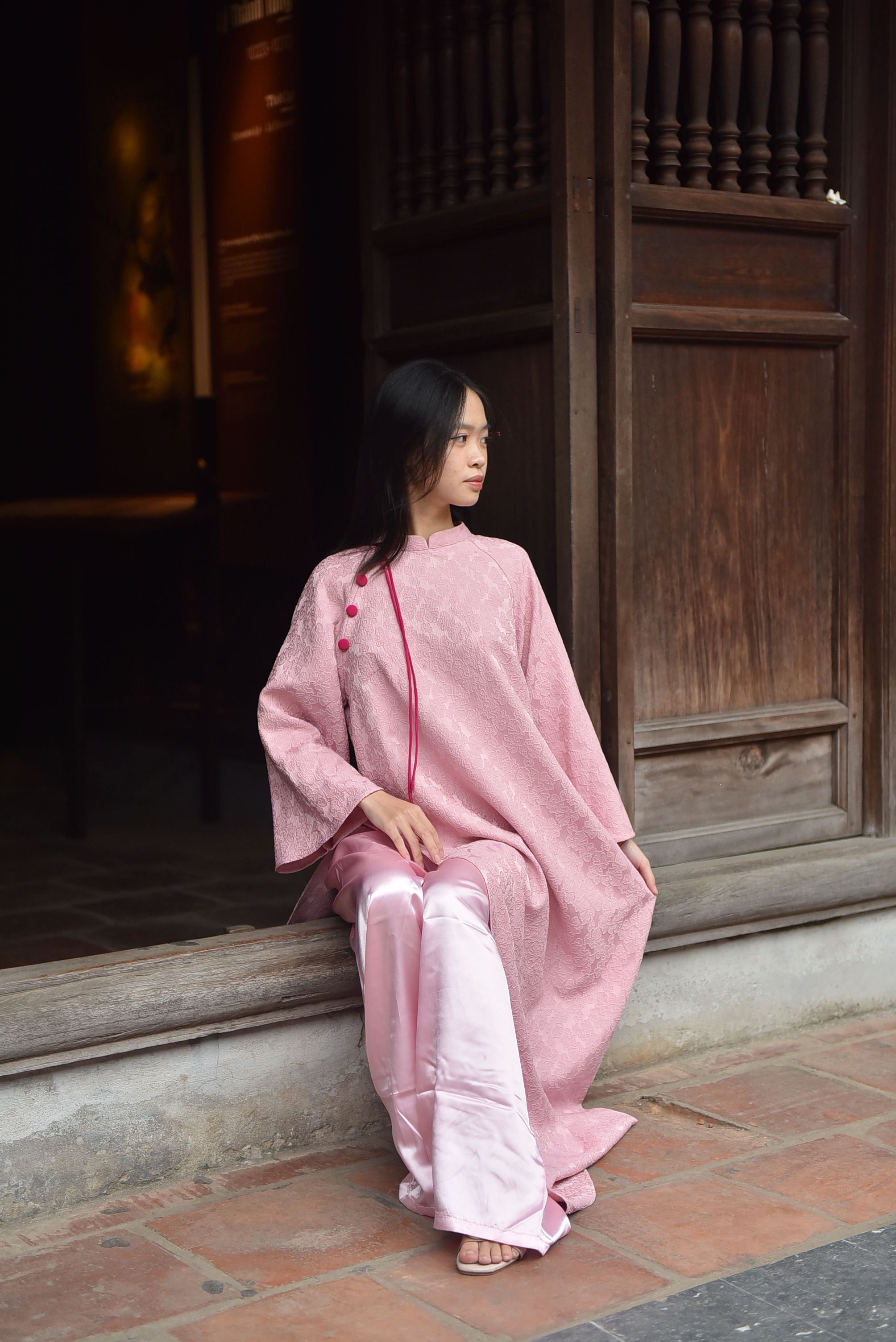 Woman in Traditional Pink Attire by Wooden Structure · Free Stock Photo