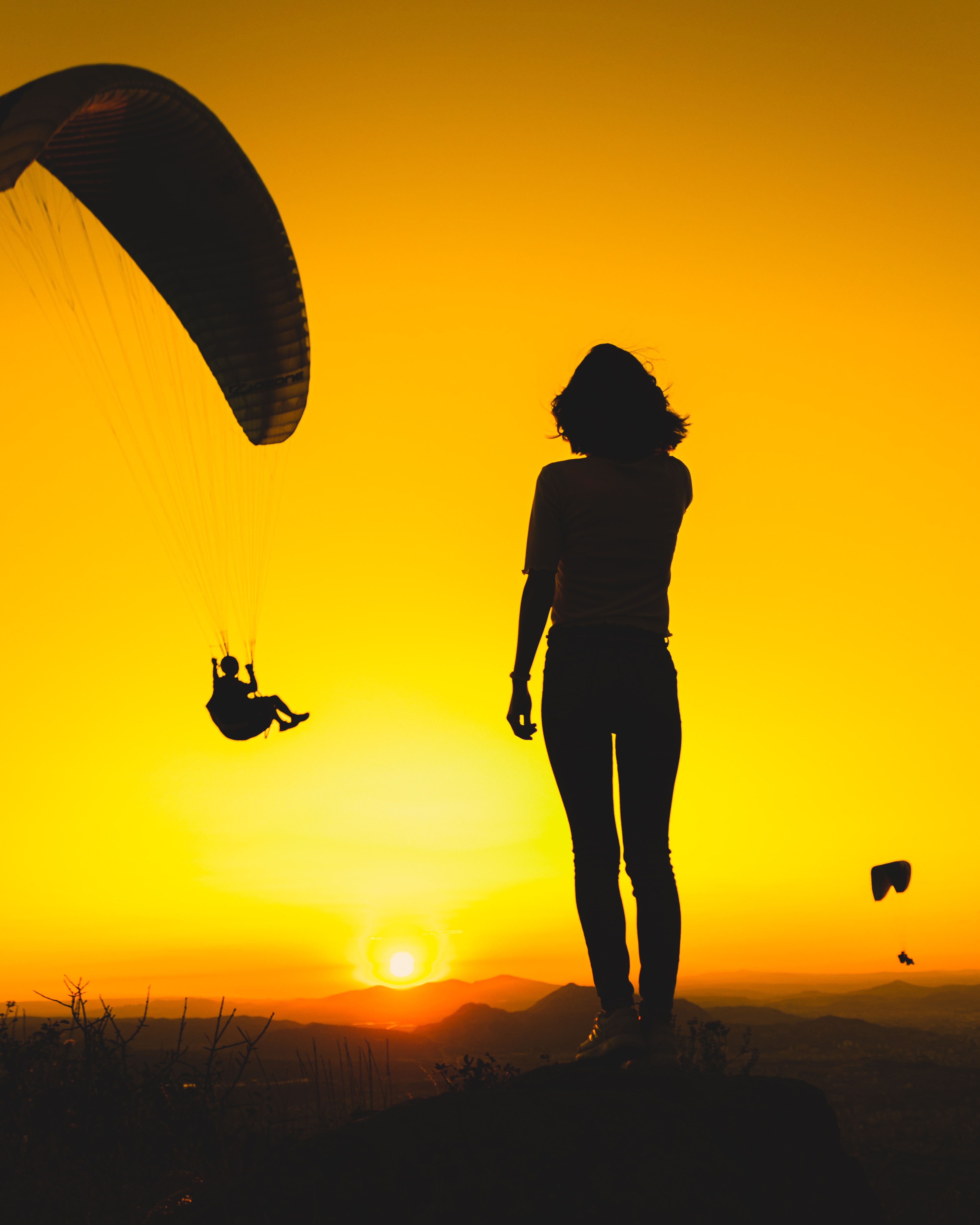 Silhouetted Paraglider and Woman at Sunset · Free Stock Photo