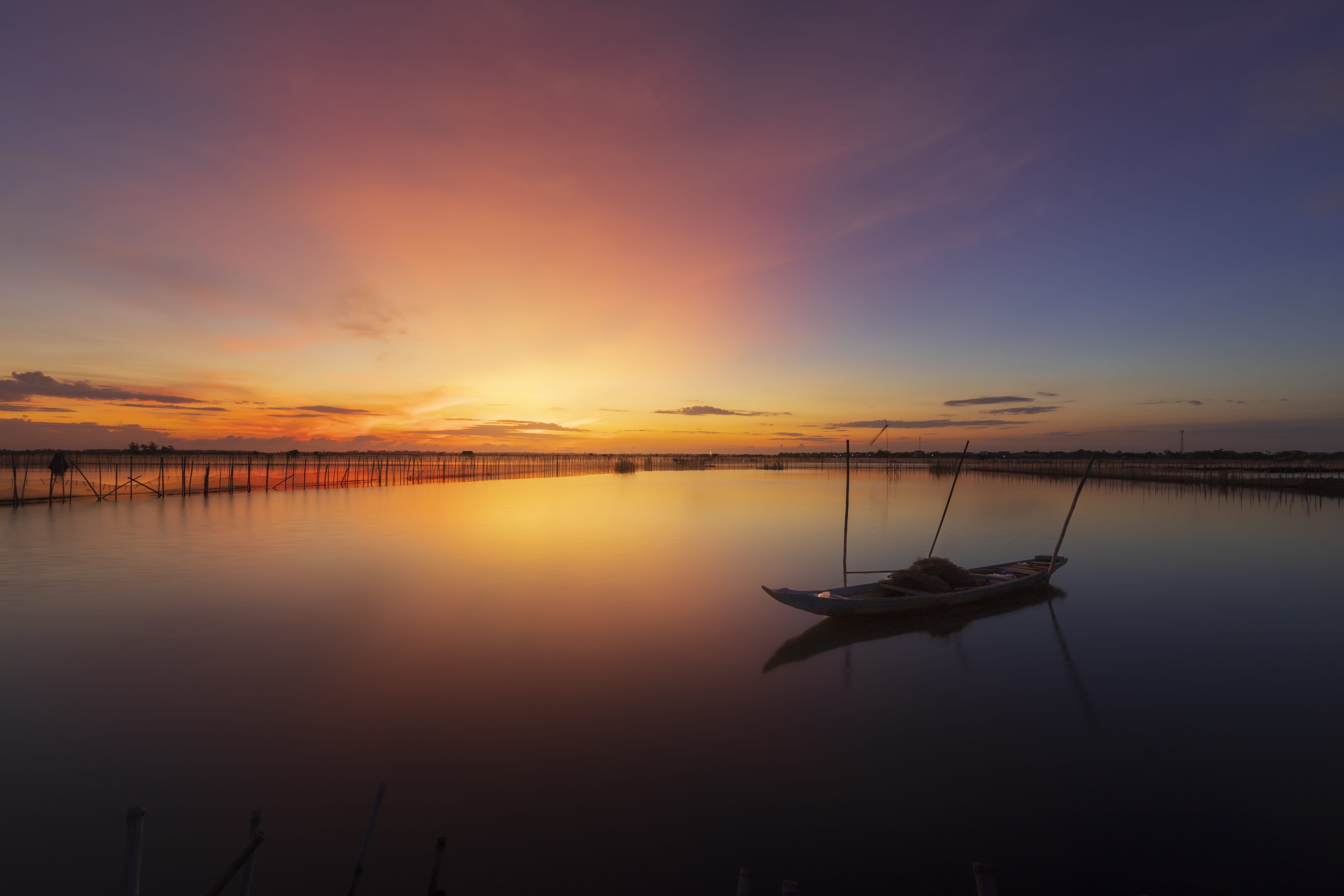 Tranquil Sunset Over Calm Lake with Boat · Free Stock Photo