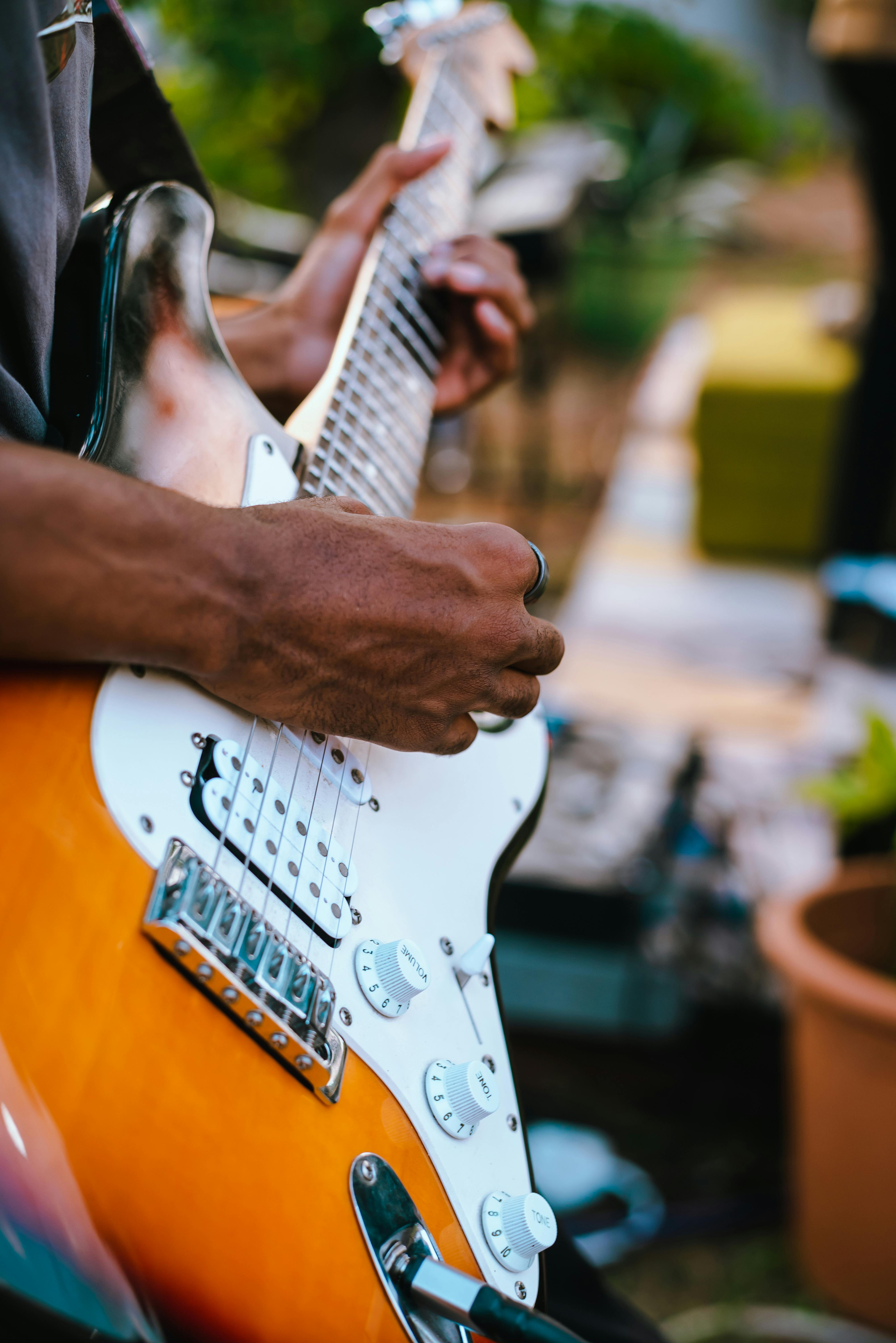 Close-Up of Hands Playing Electric Guitar Outdoors · Free Stock Photo