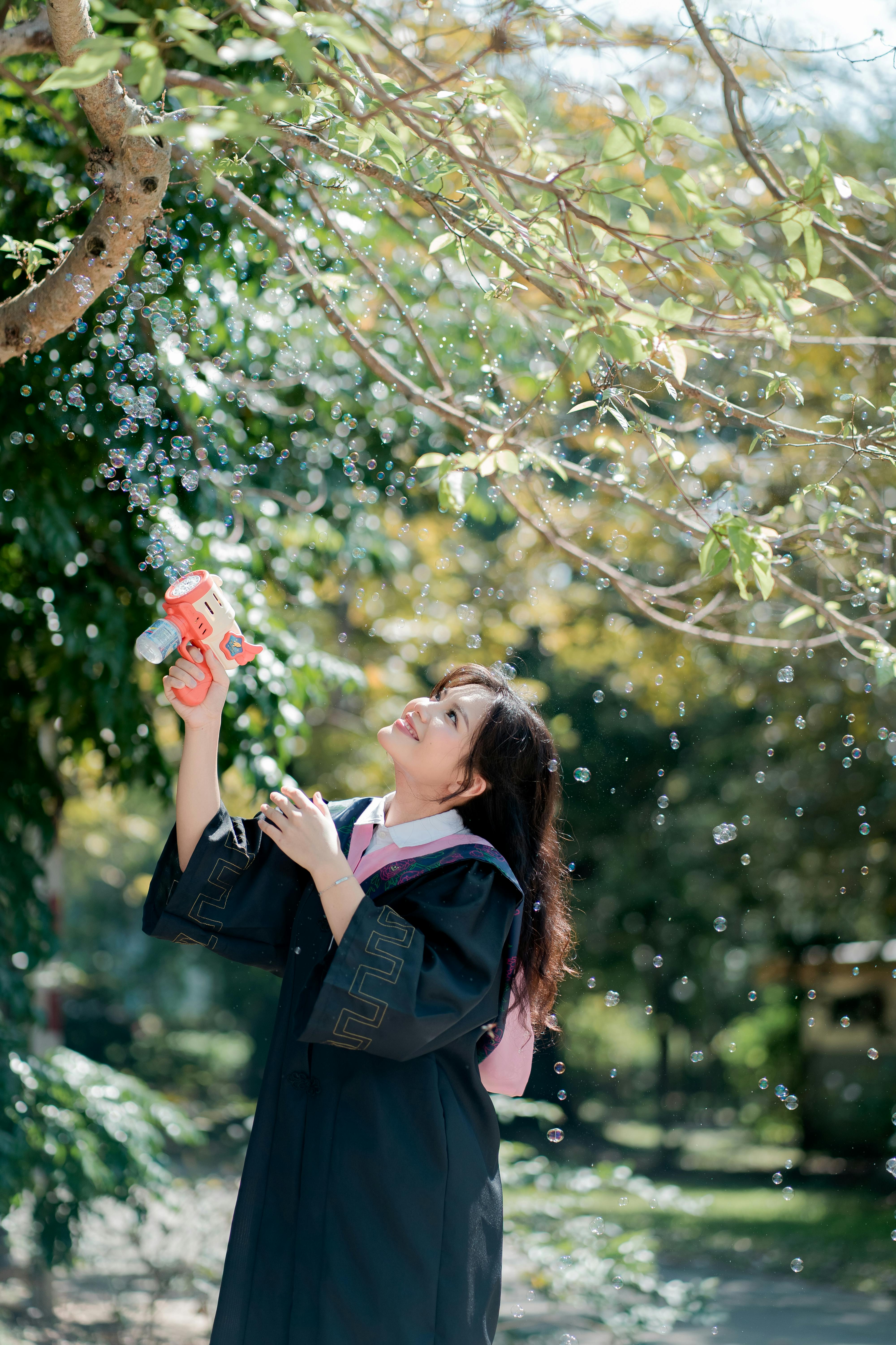 Young Adult Celebrating Graduation Outdoors with Bubbles · Free Stock Photo