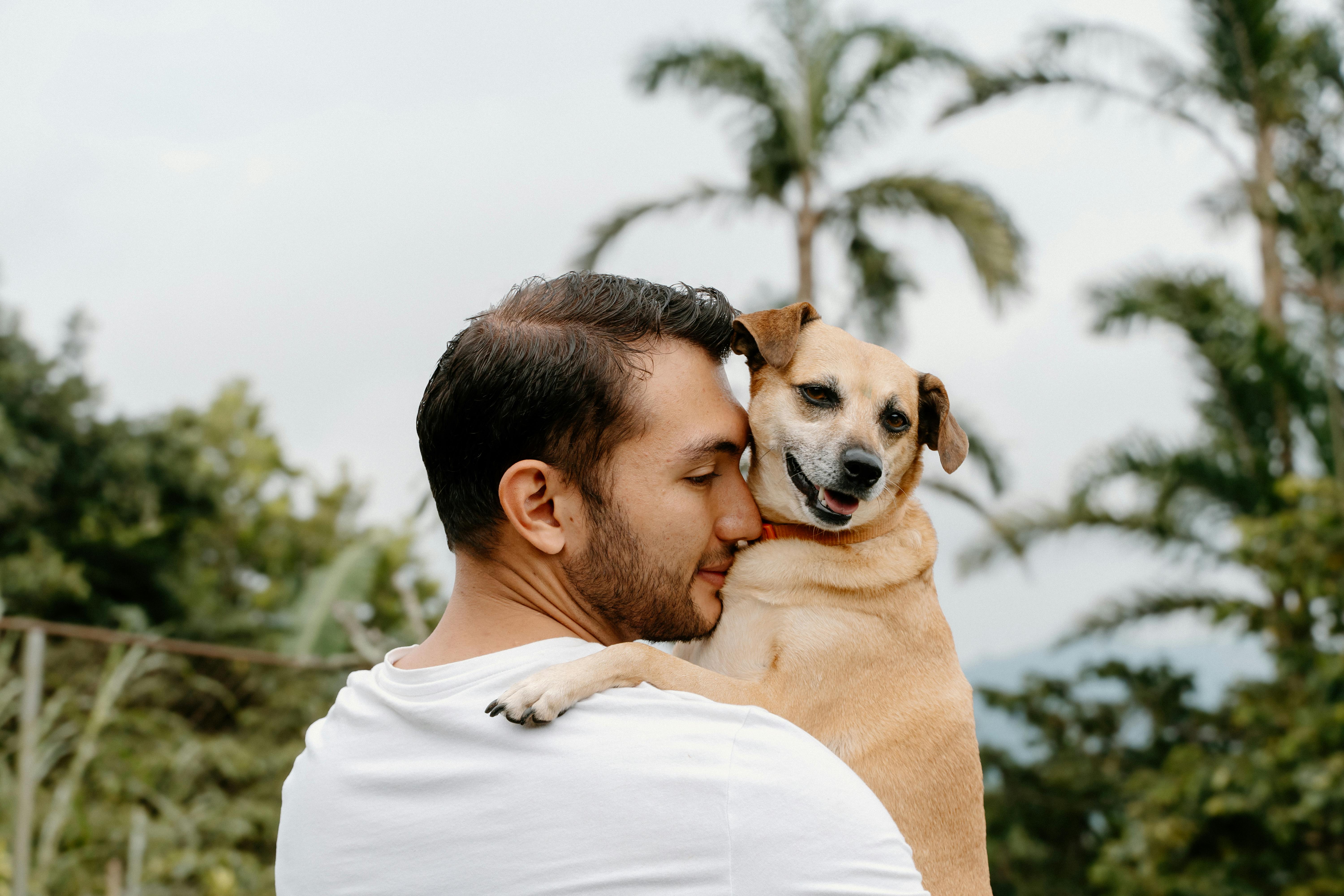 Man Embracing Dog in Tropical Costa Rican Setting · Free Stock Photo