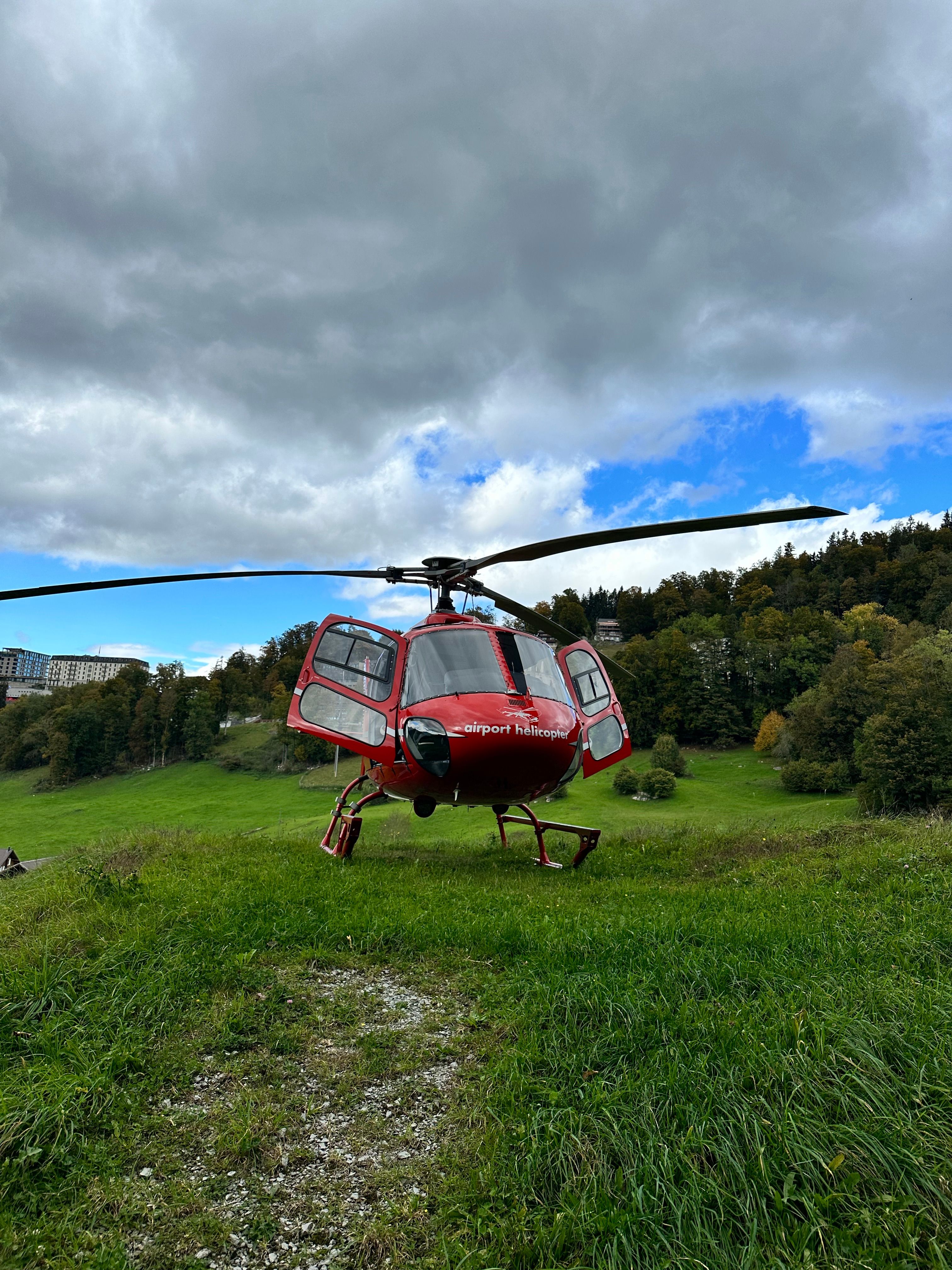 Red Helicopter Landing in Scenic Open Field · Free Stock Photo