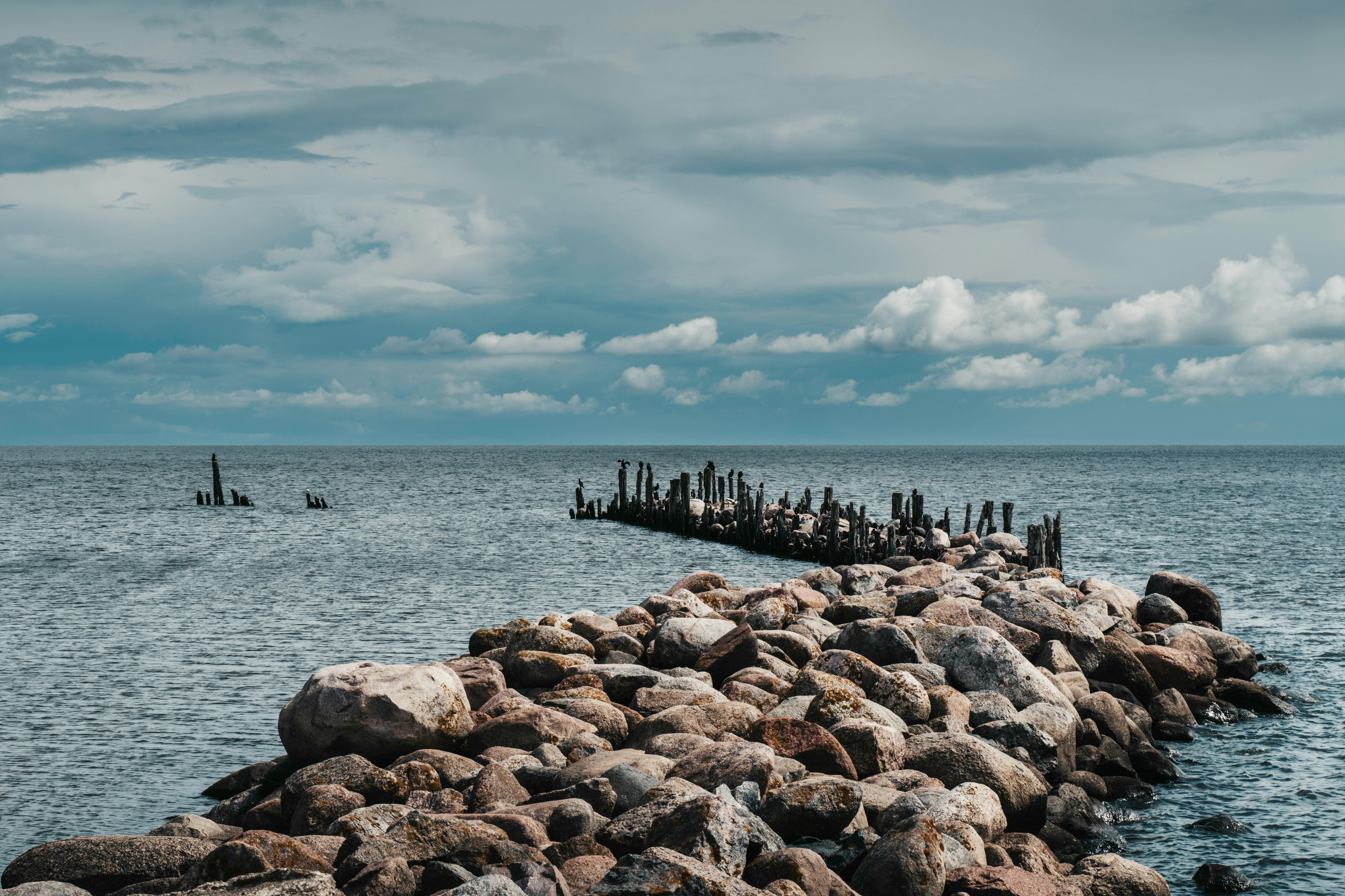 Rustic Rock Jetty Extending Into Serene Ocean · Free Stock Photo