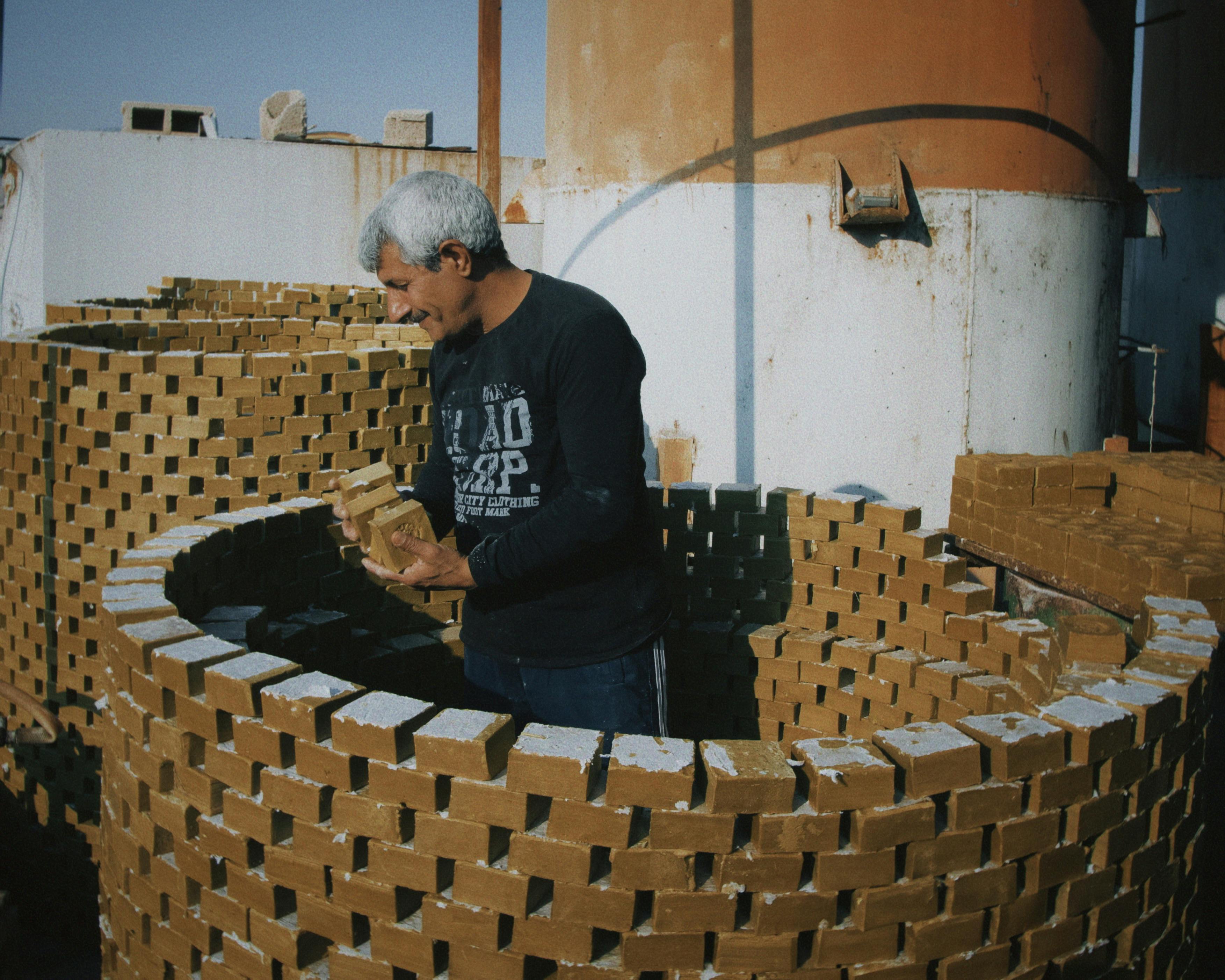 Man Building Brick Structure at Industrial Site · Free Stock Photo