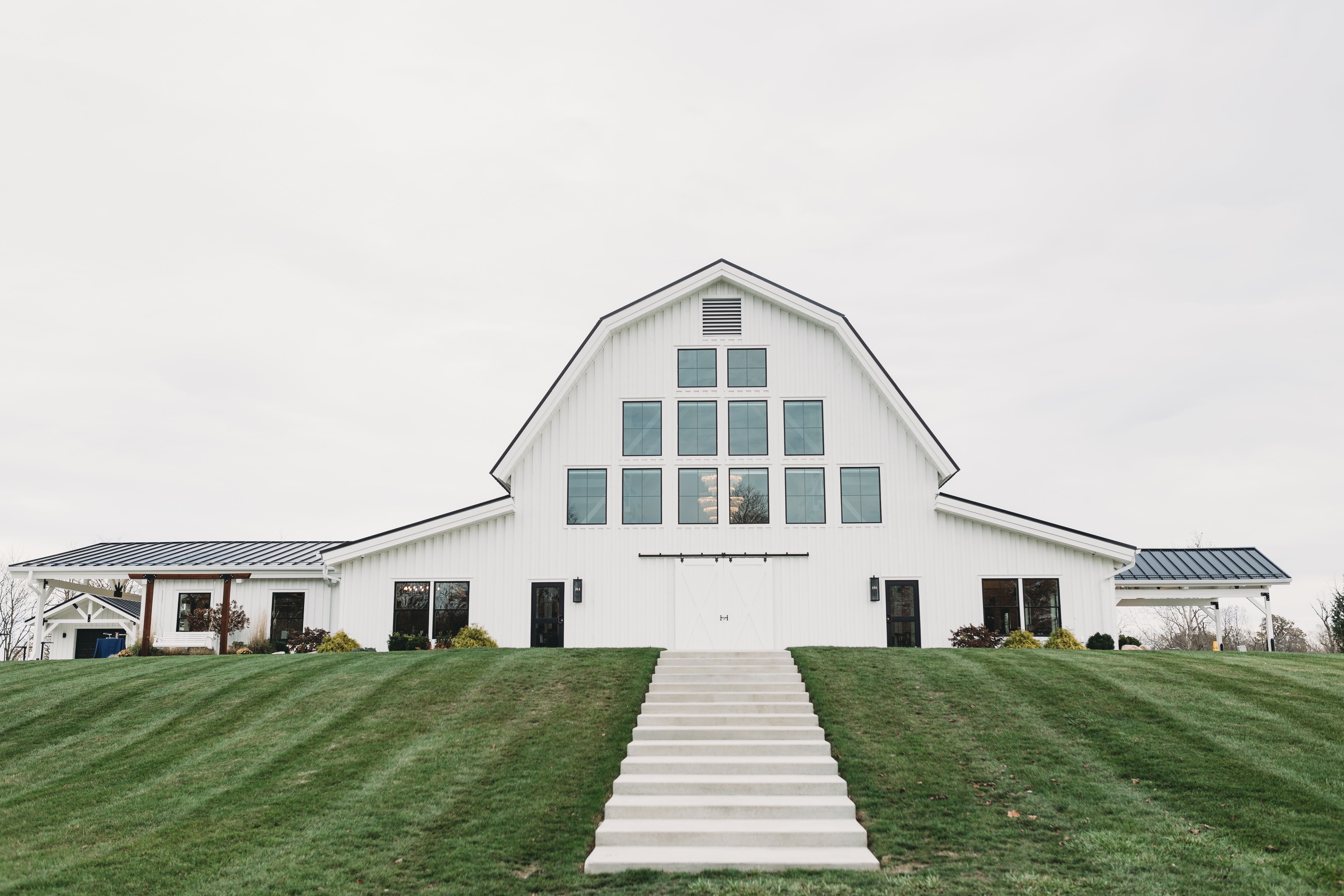 Elegant White Barn Venue Amidst Lush Greens · Free Stock Photo