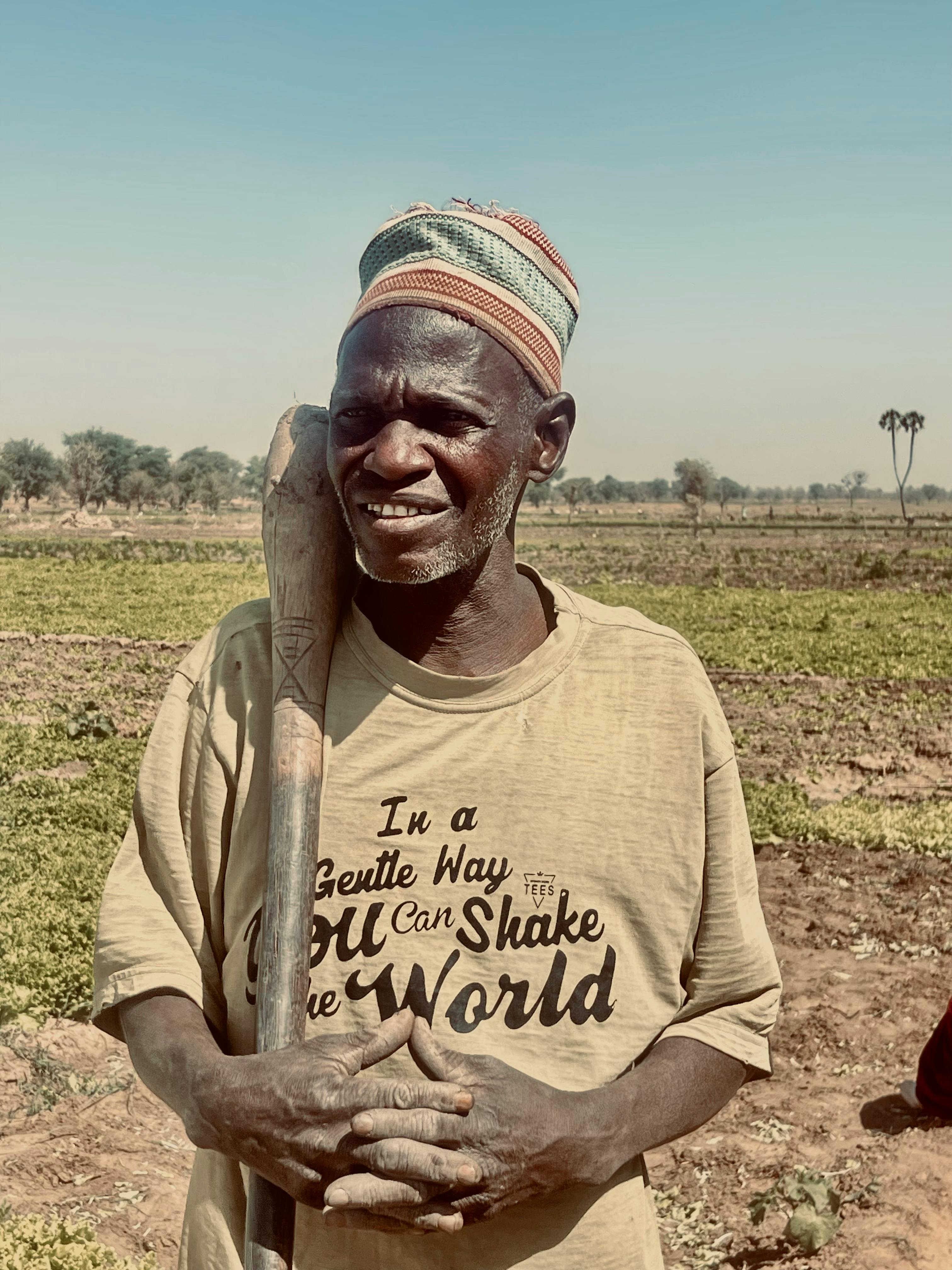 African Farmer Standing in a Field with Hoe · Free Stock Photo