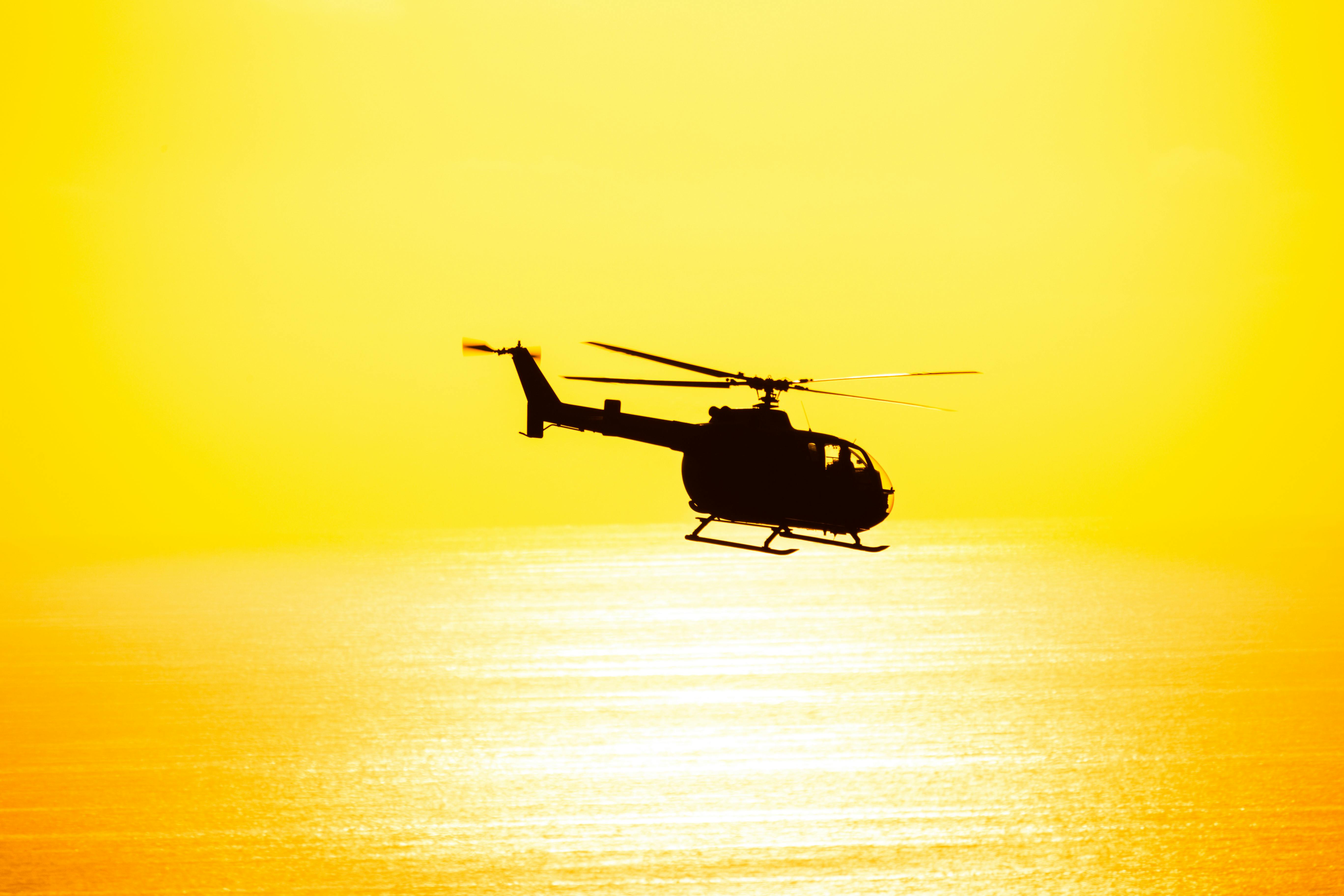 Silhouette of Helicopter Flying Over Ocean at Sunset · Free Stock Photo
