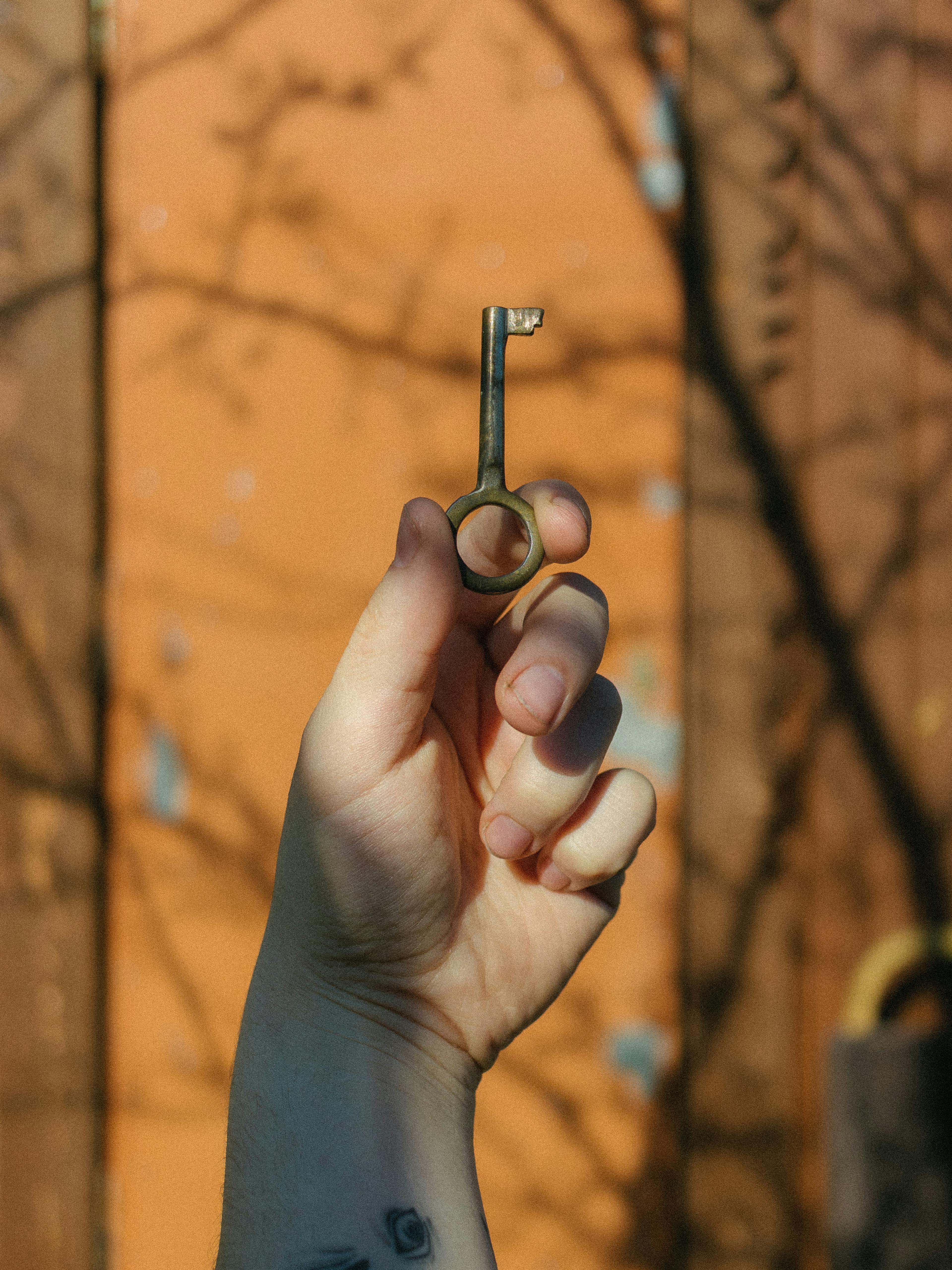 Person Holding Antique Key with Shadow Play · Free Stock Photo
