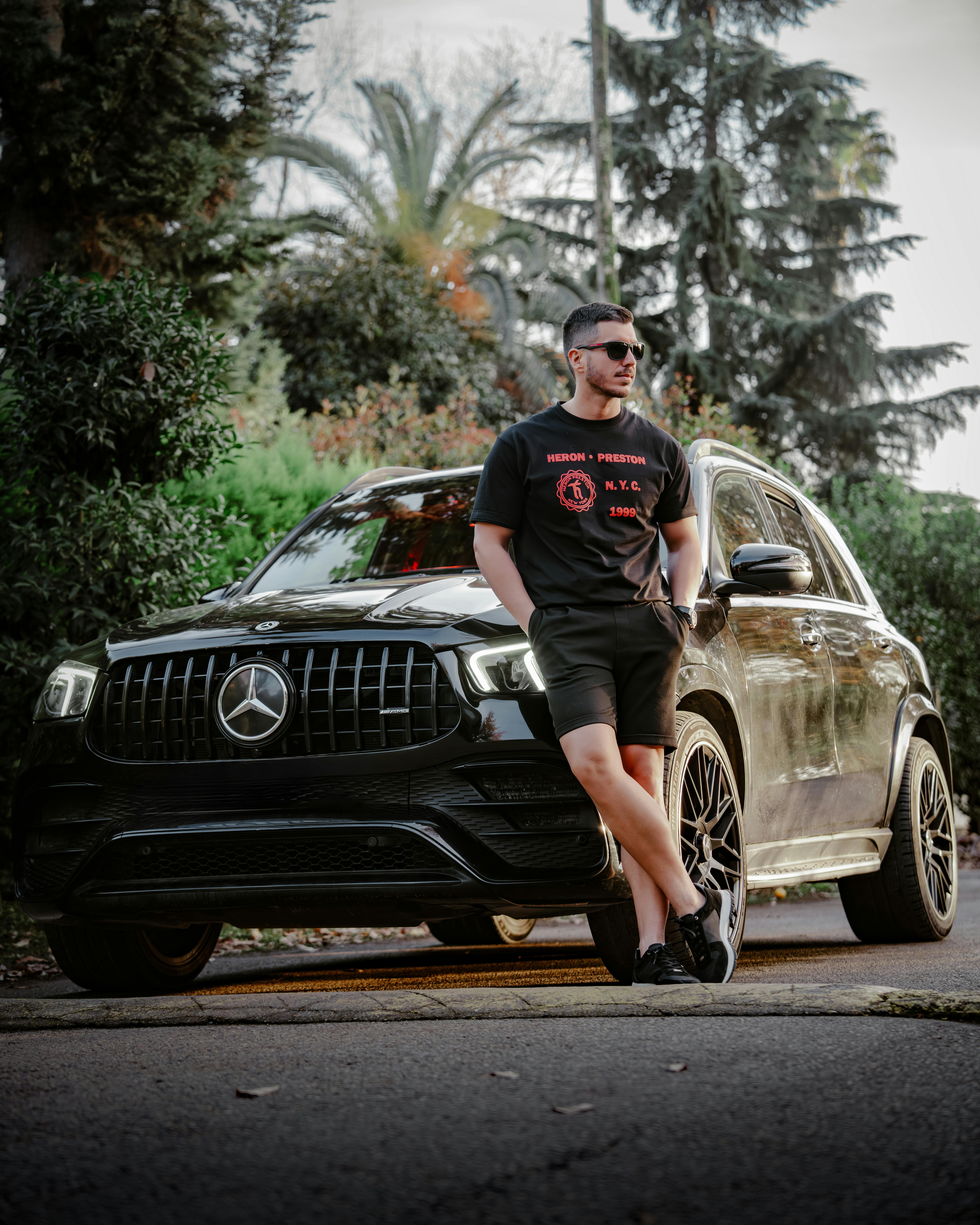 Young Man Leaning on Luxury Black Mercedes SUV · Free Stock Photo