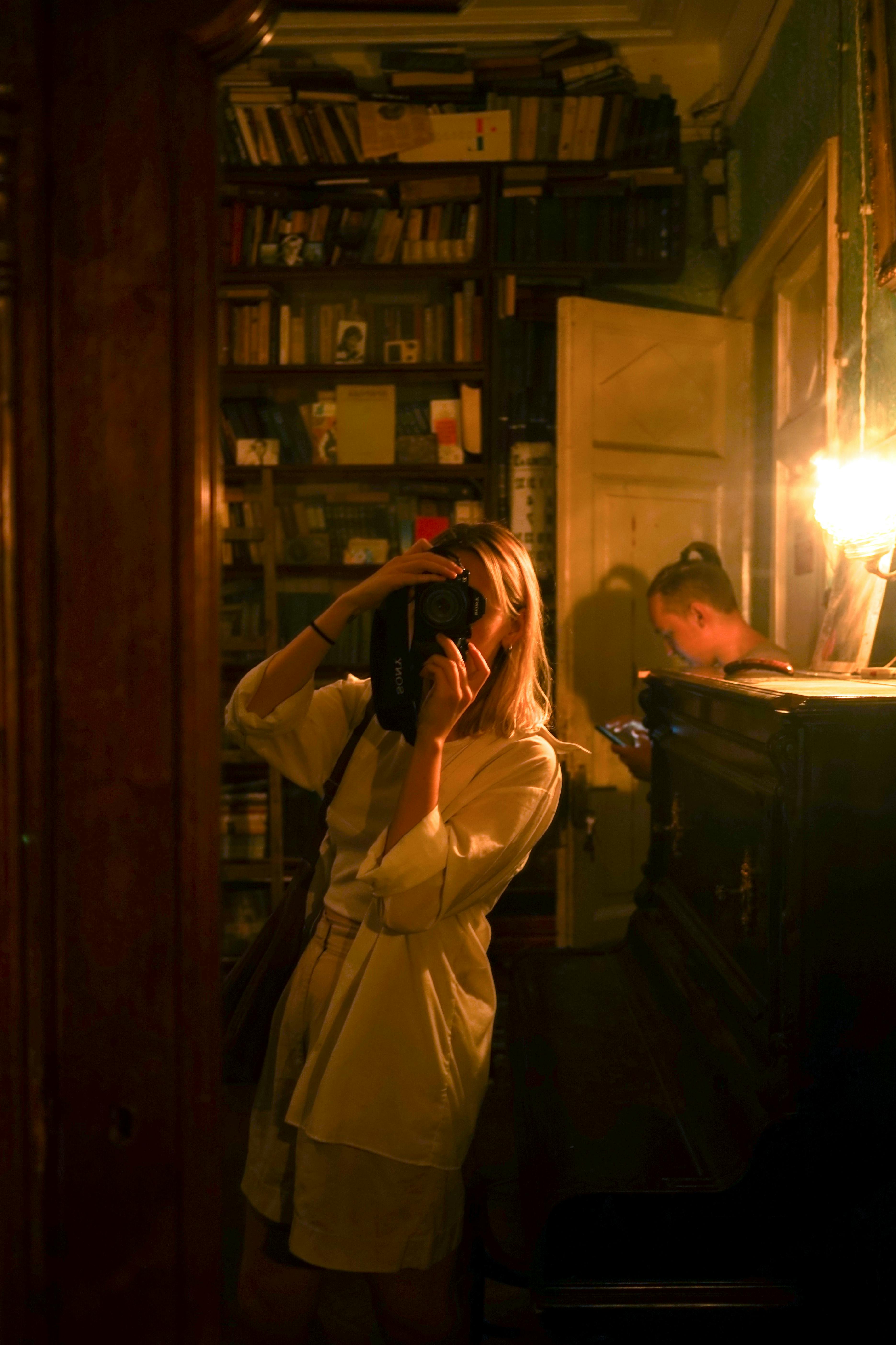 Cozy Home Library with Photographer and Books · Free Stock Photo