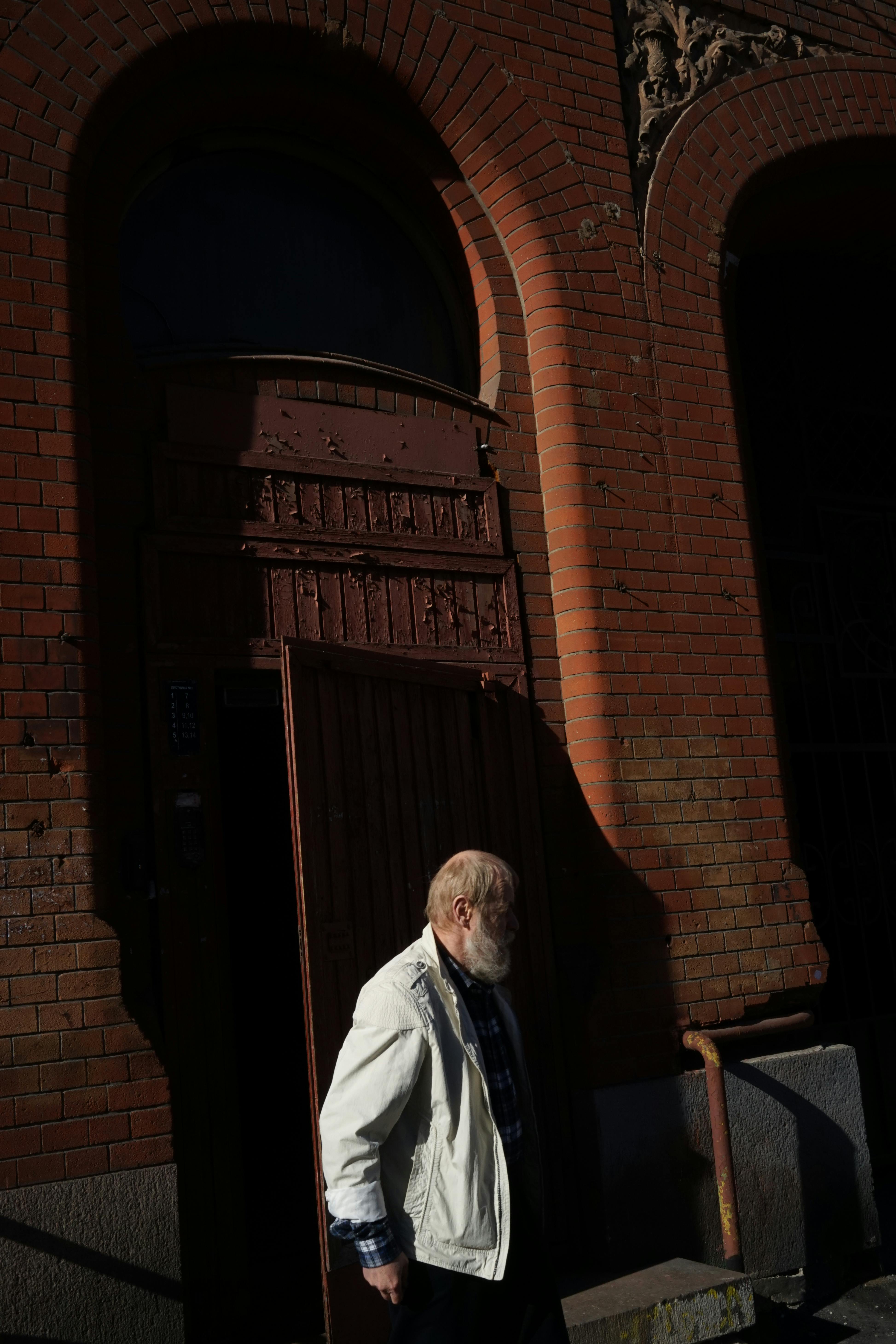Elderly Man Exiting Building in Dark Lighting · Free Stock Photo