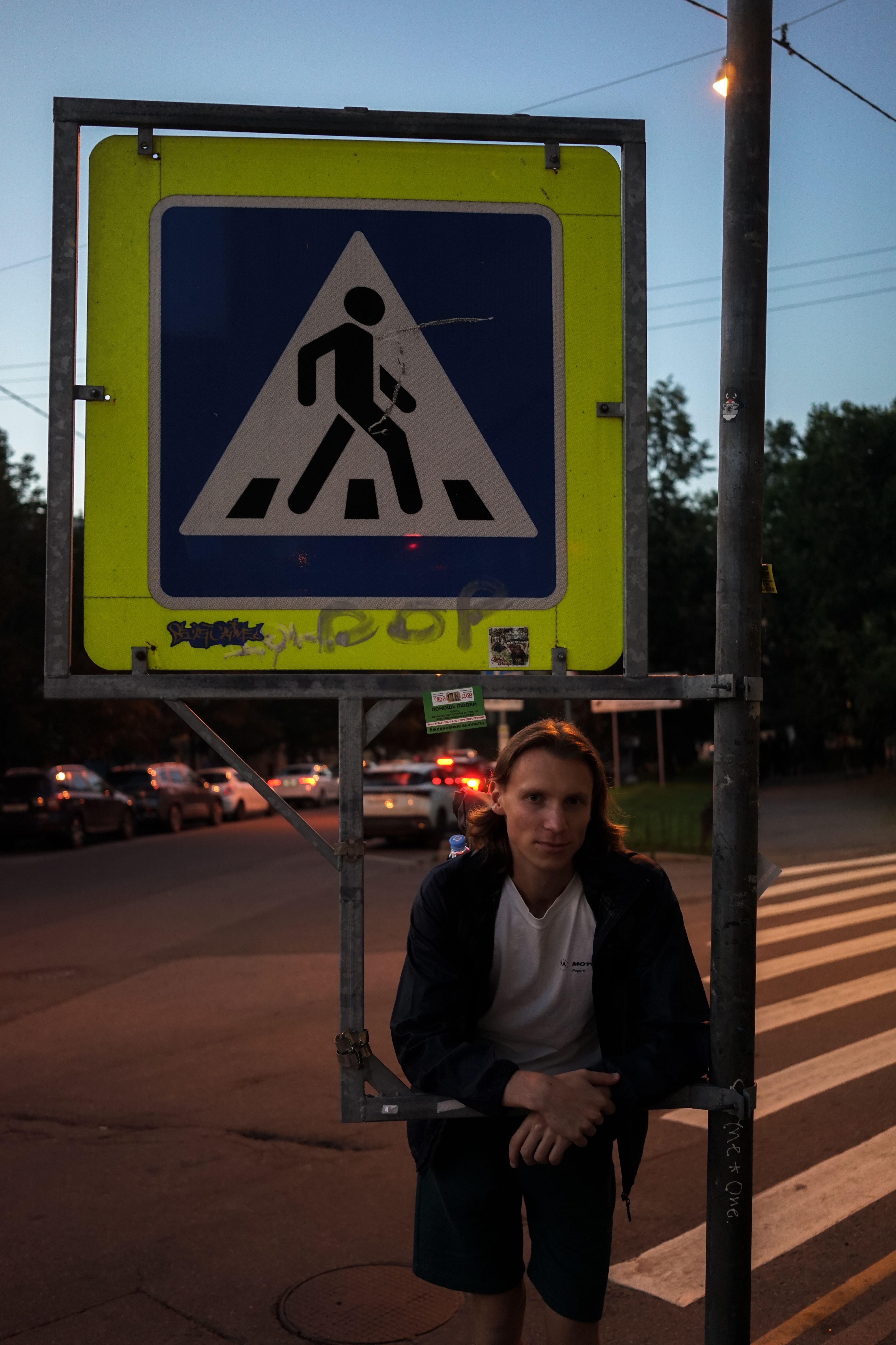 Young Adult Under Street Sign at Dusk · Free Stock Photo