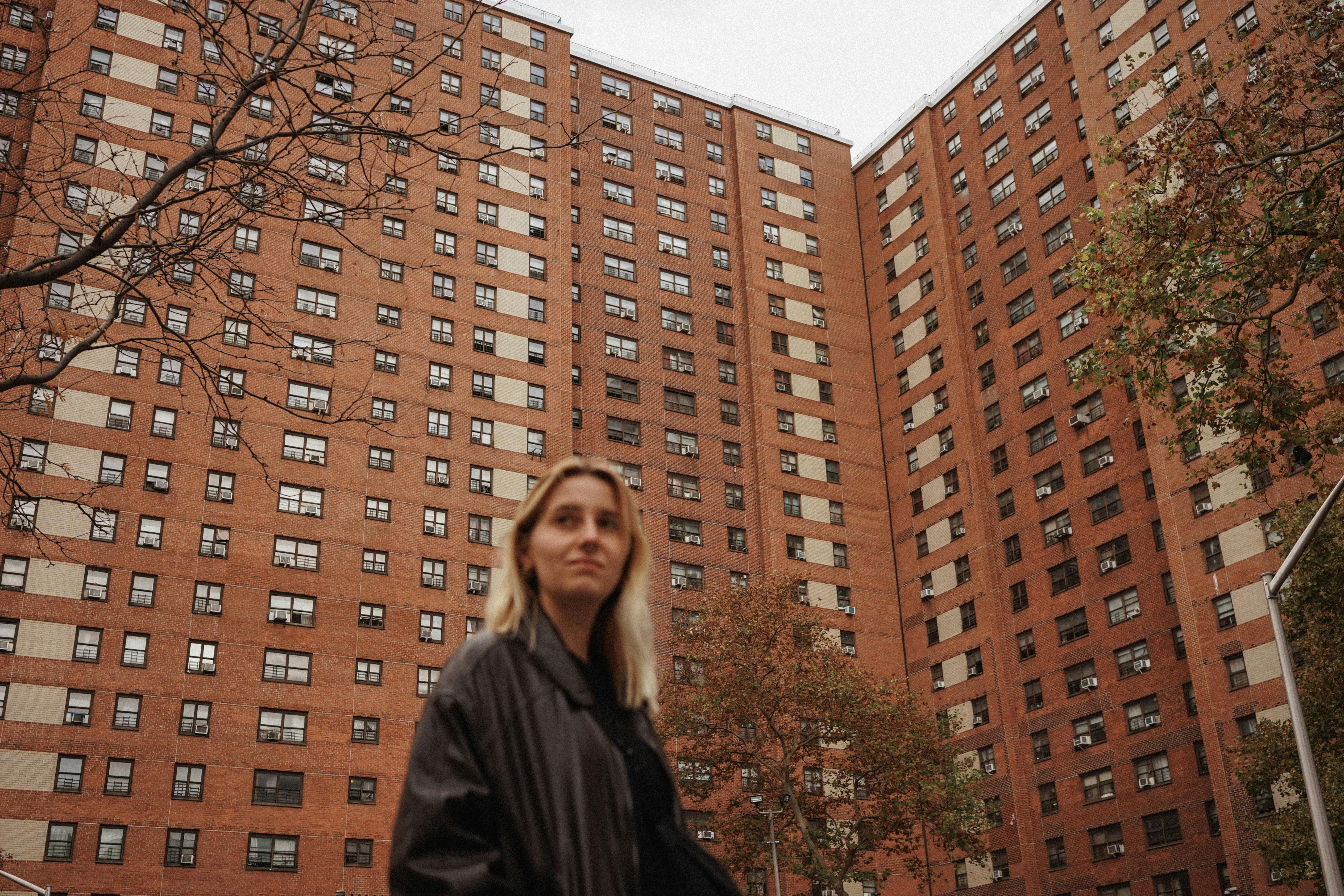 Woman in Urban Setting with Tall Brick Buildings · Free Stock Photo