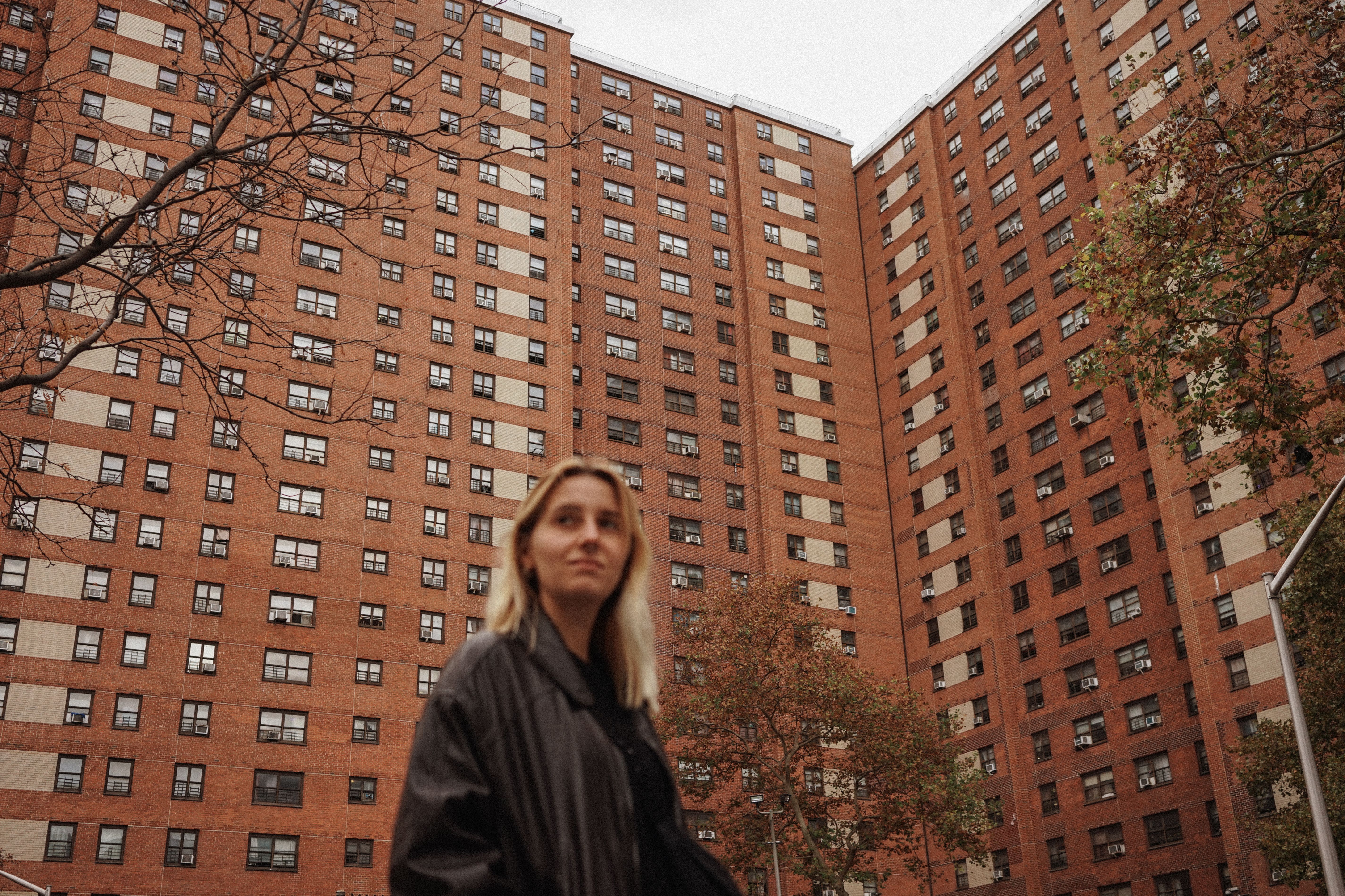 Woman in Urban Setting with Tall Brick Buildings · Free Stock Photo