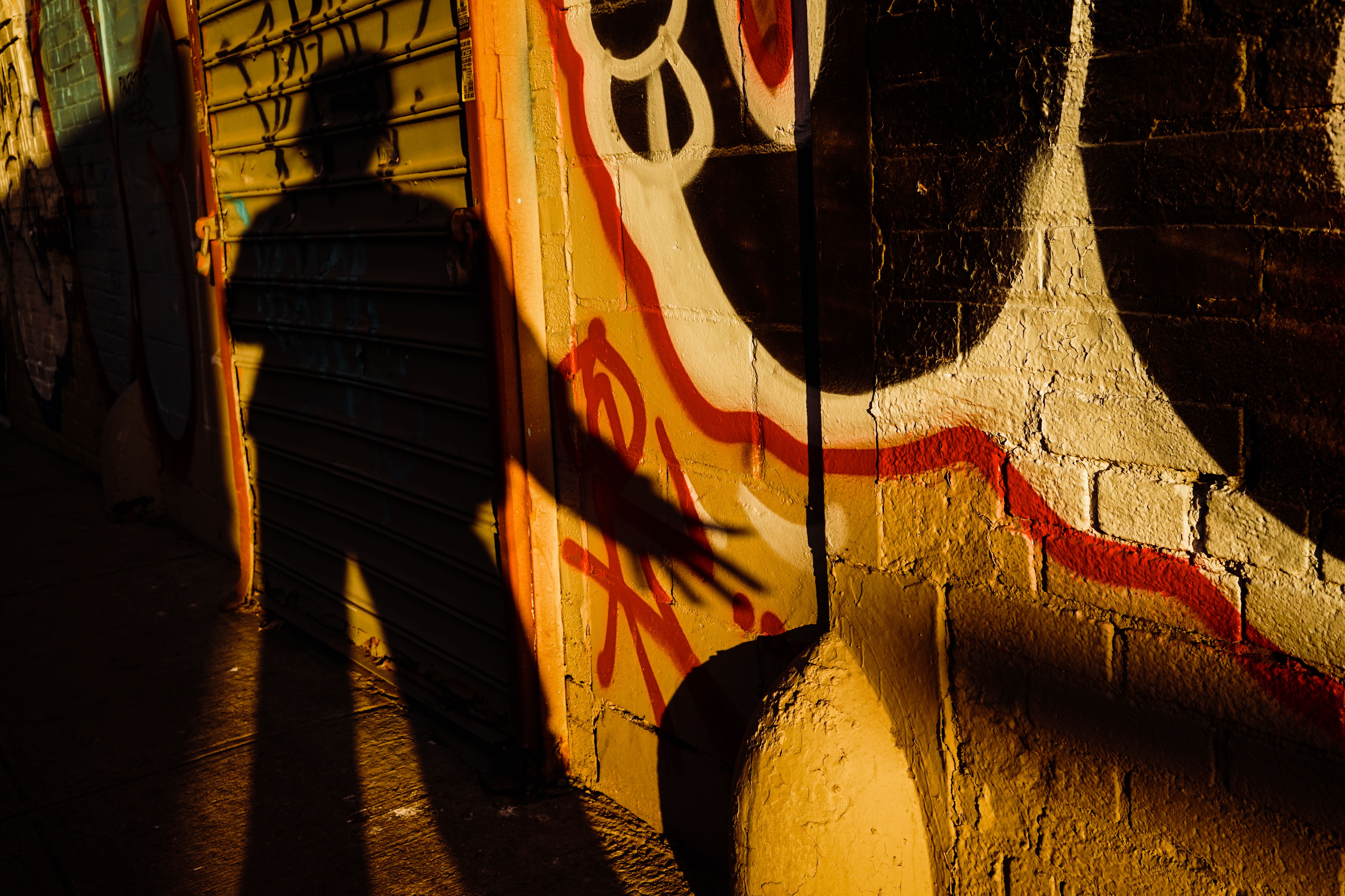 Shadow Cast on Graffiti Wall at Sunset · Free Stock Photo