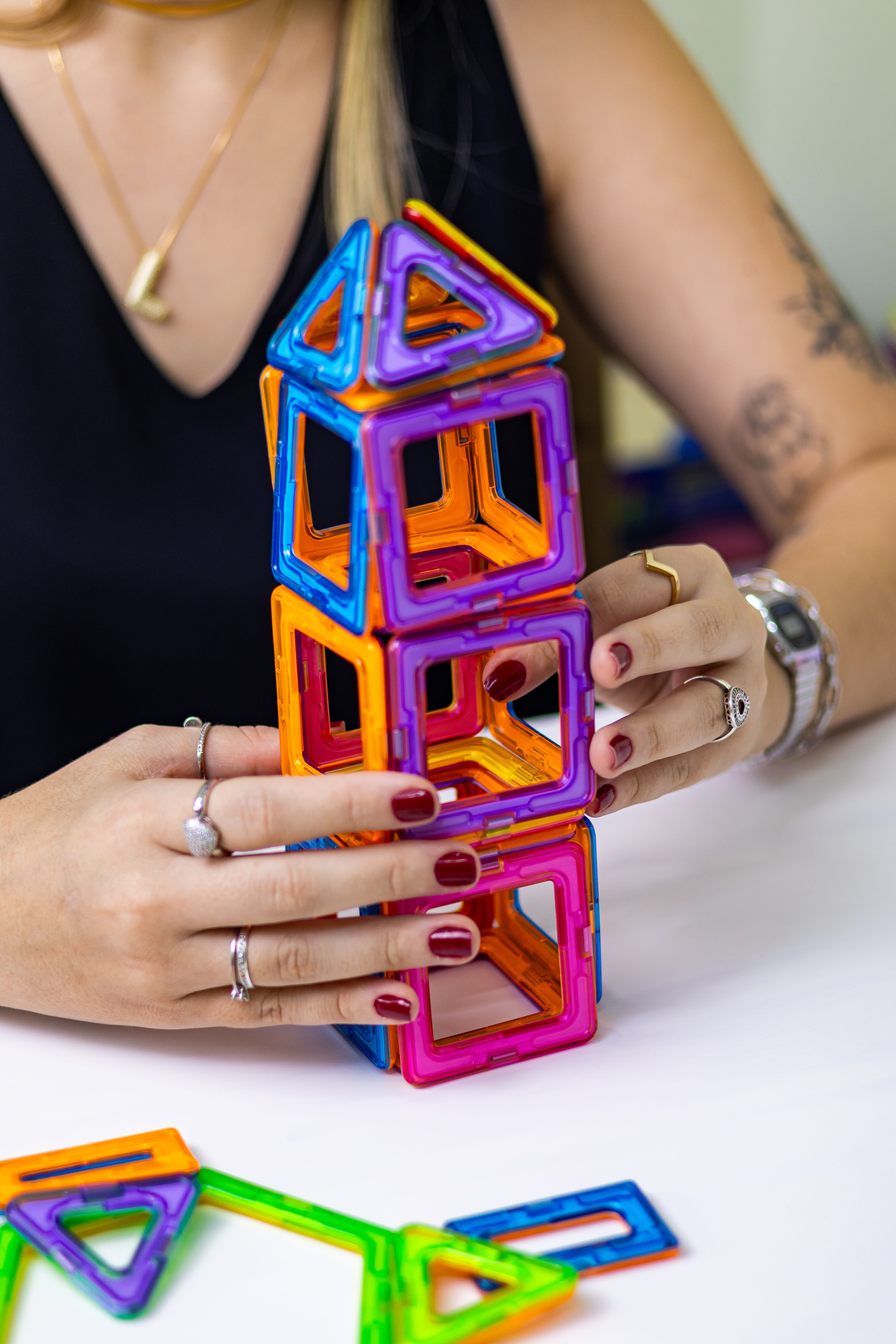Hands Building Colorful Geometric Toy Tower · Free Stock Photo