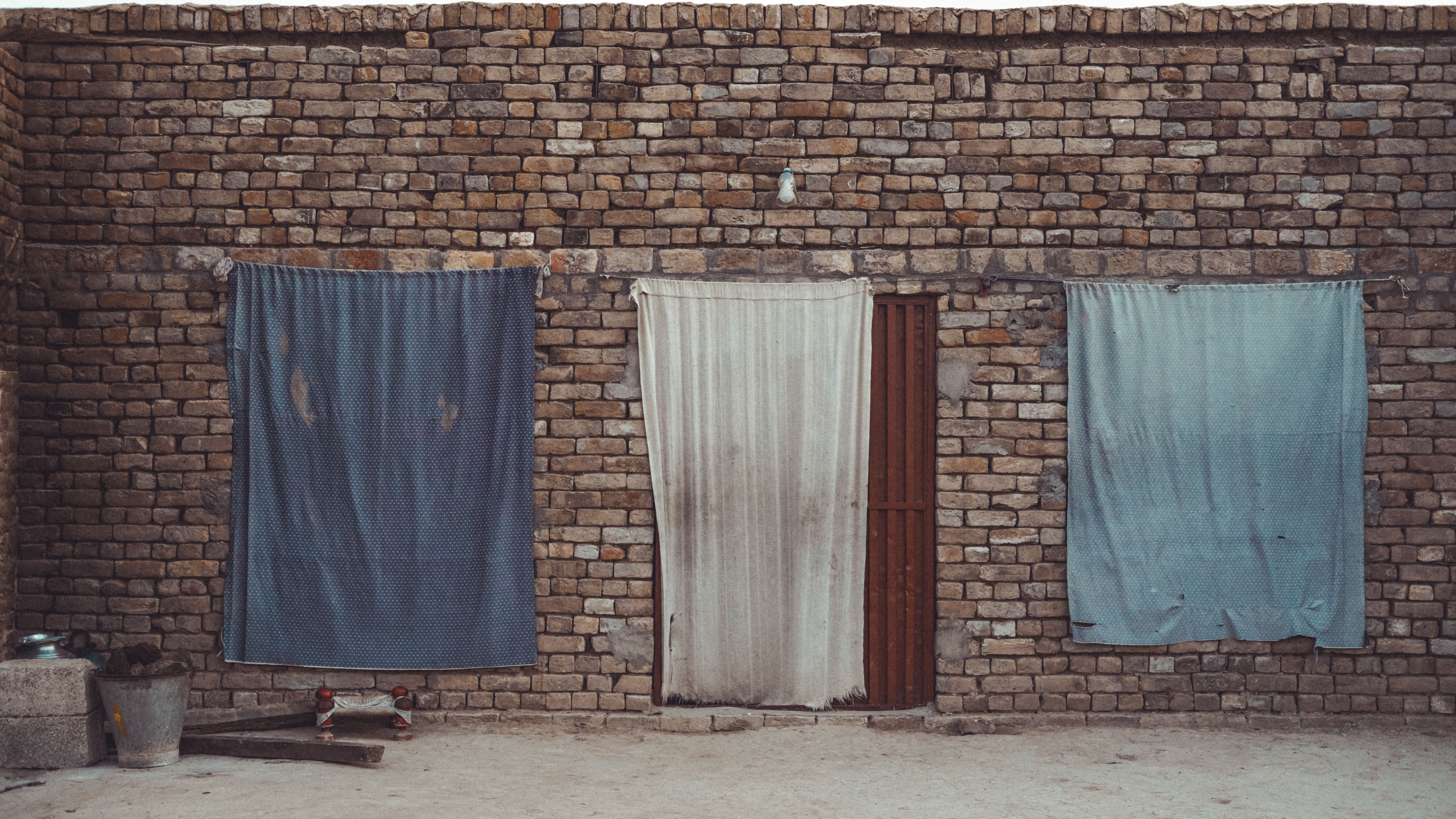 Rustic Brick Wall with Hanging Fabrics · Free Stock Photo
