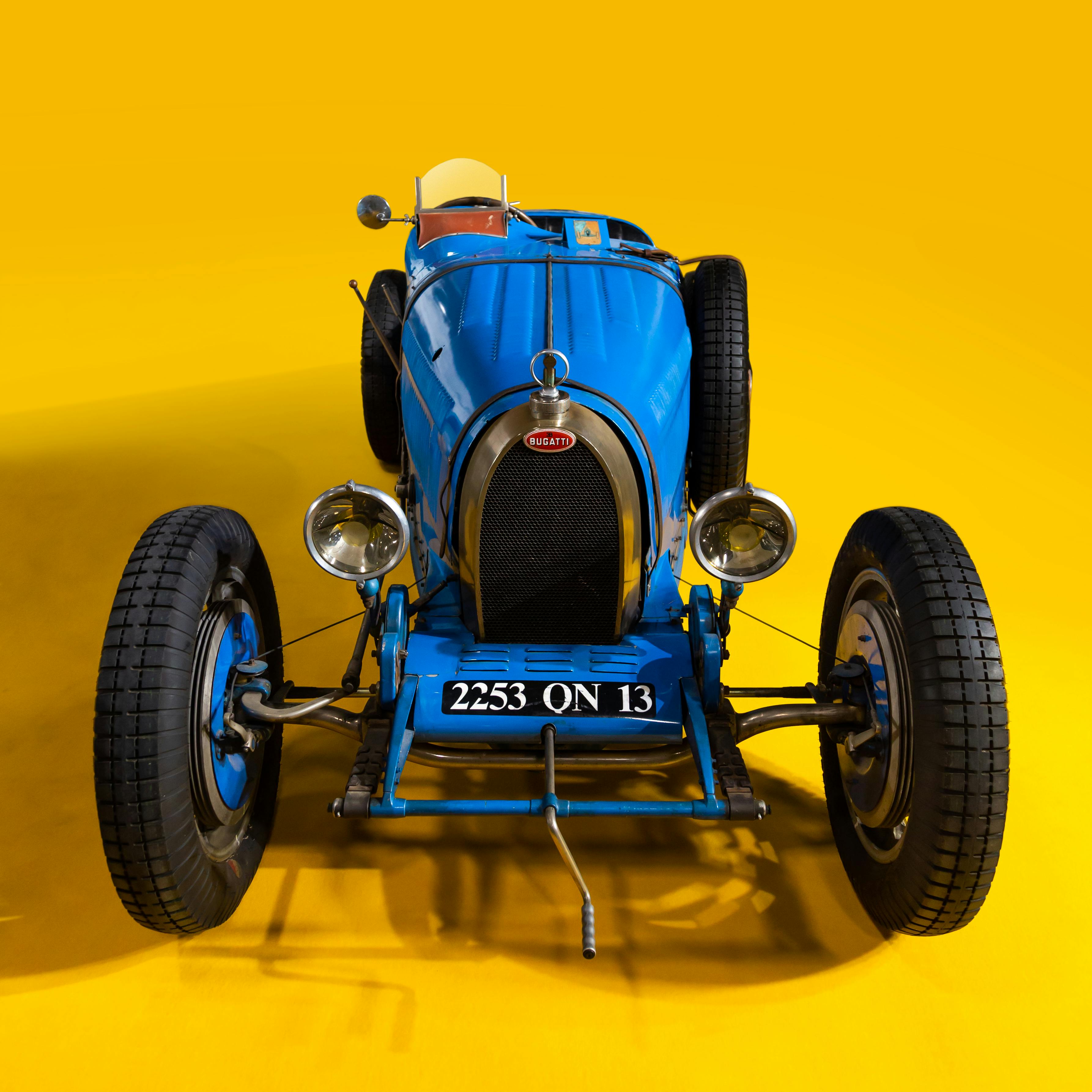 Vintage Blue Bugatti Racing Car on Yellow Background · Free Stock Photo